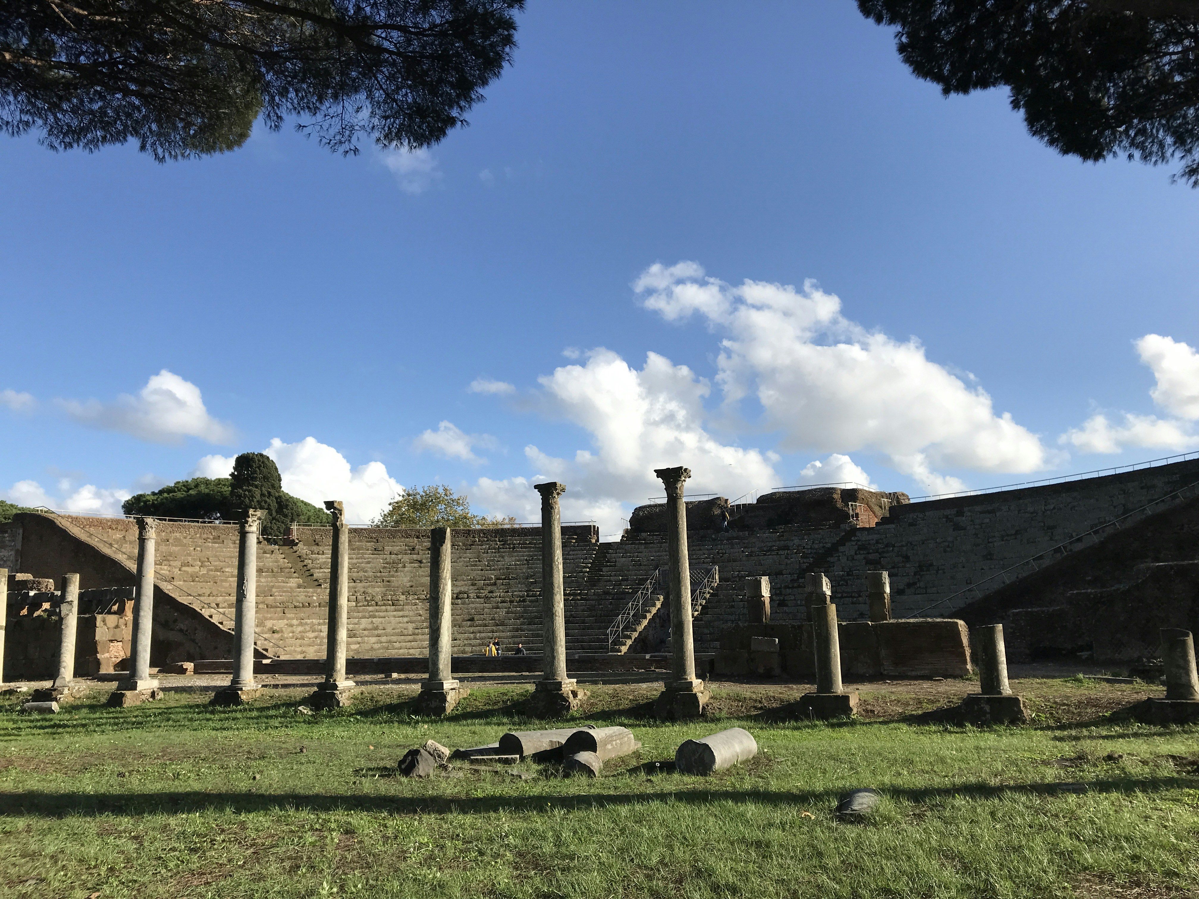 Stone columns and ruins set against a bright blue sky with scattered clouds.