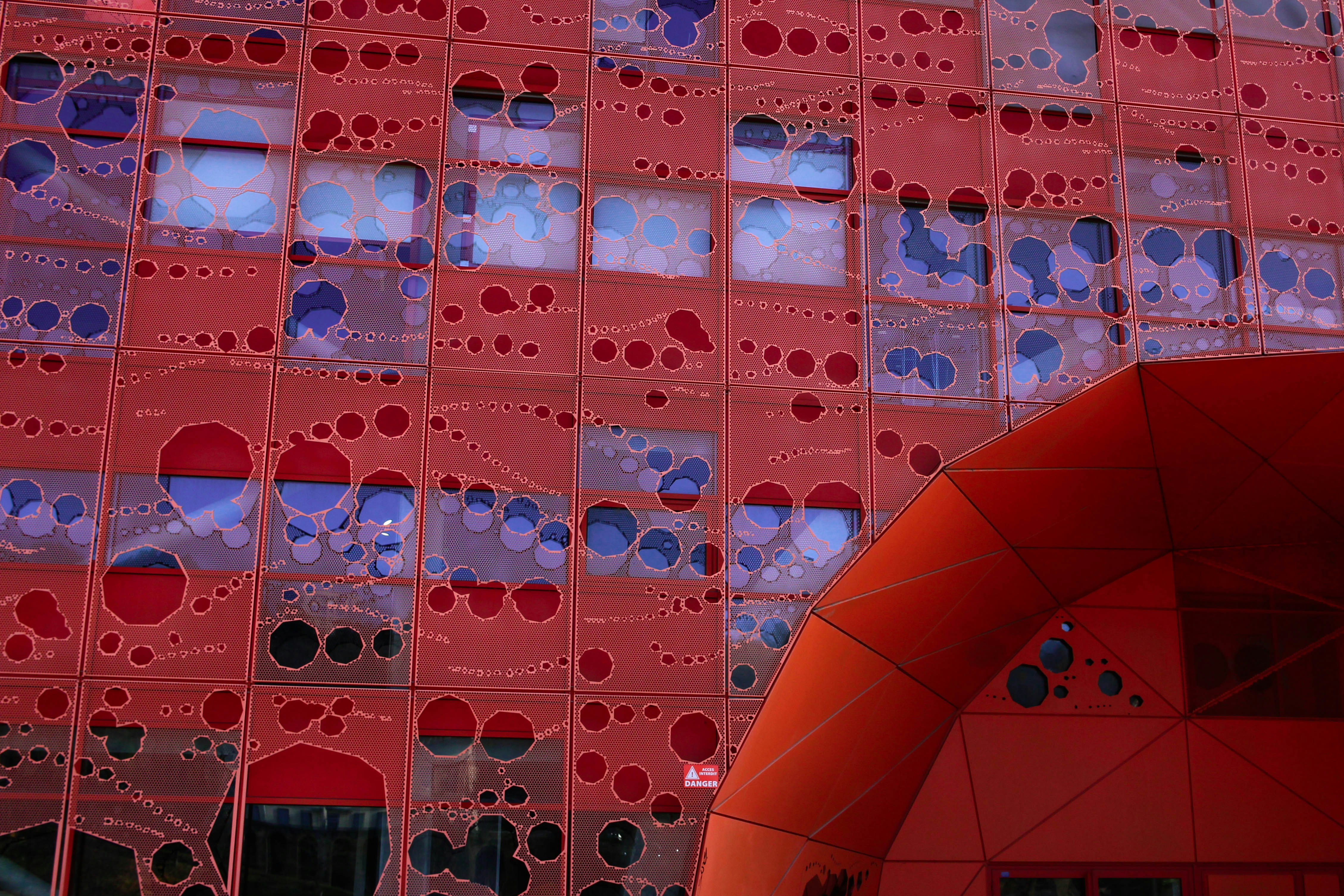 Red Perforated Facade Meets Orange Arch: Geometry and Color