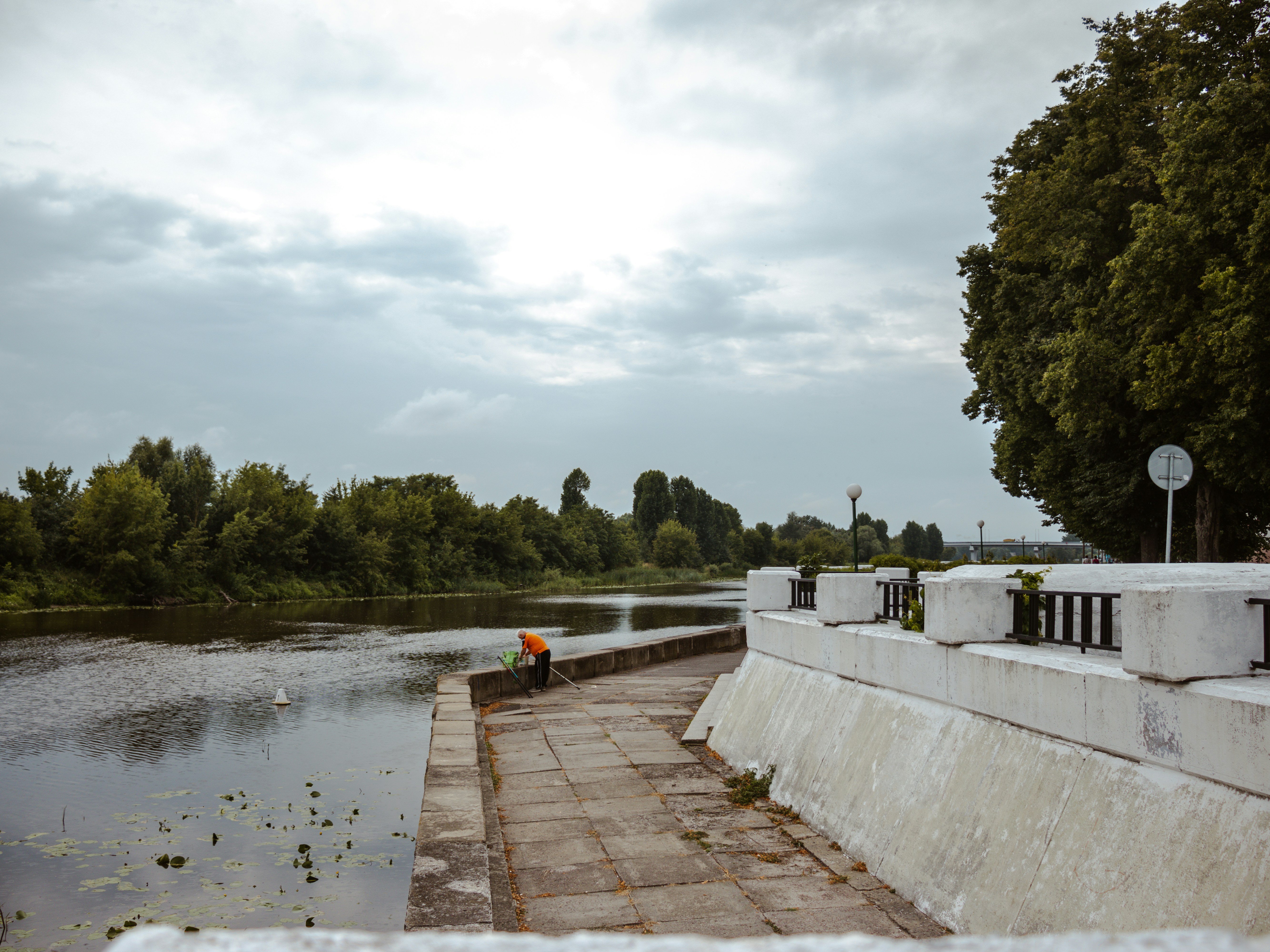 a man sitting on a bench next to a river