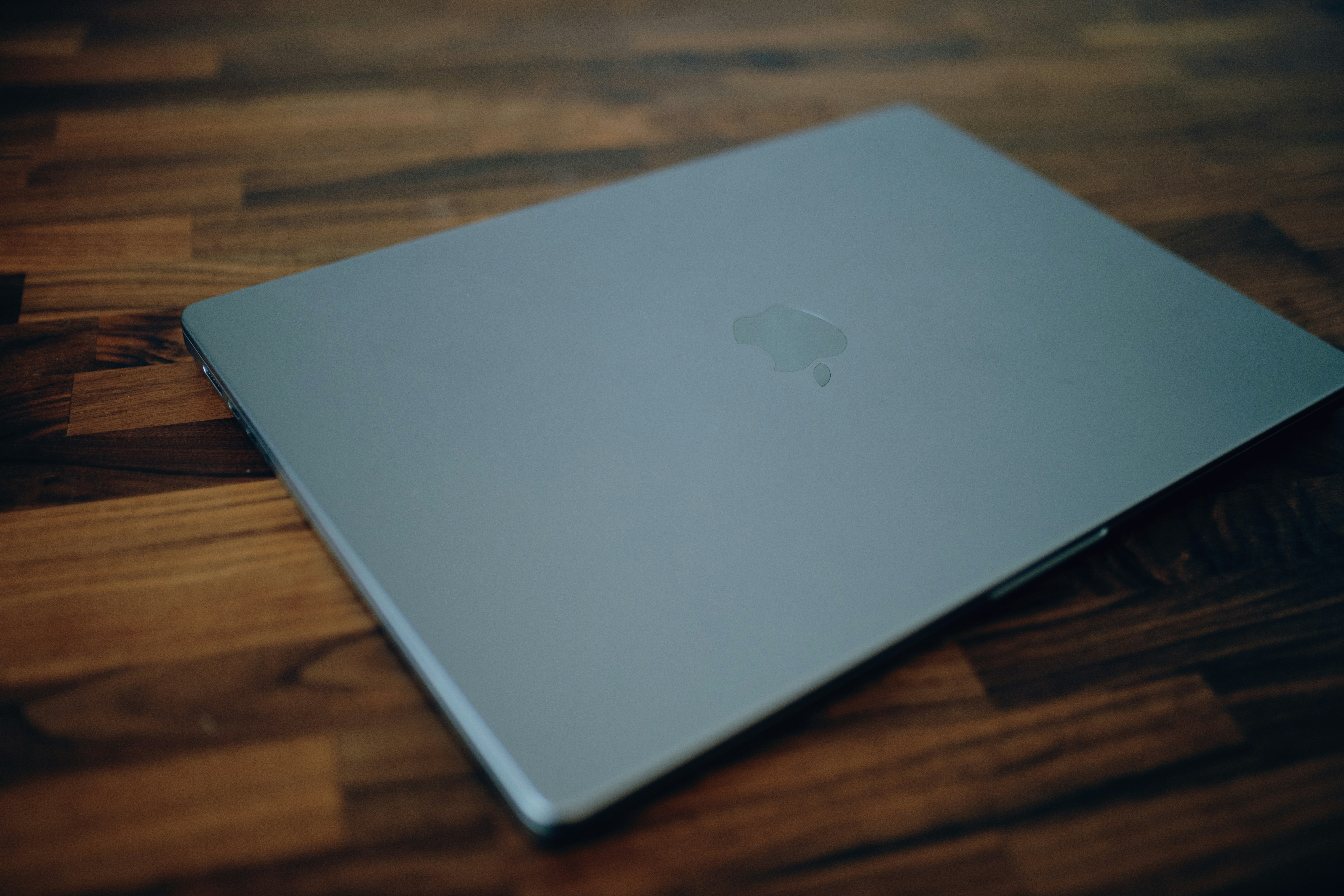 a silver apple laptop sitting on a wooden table