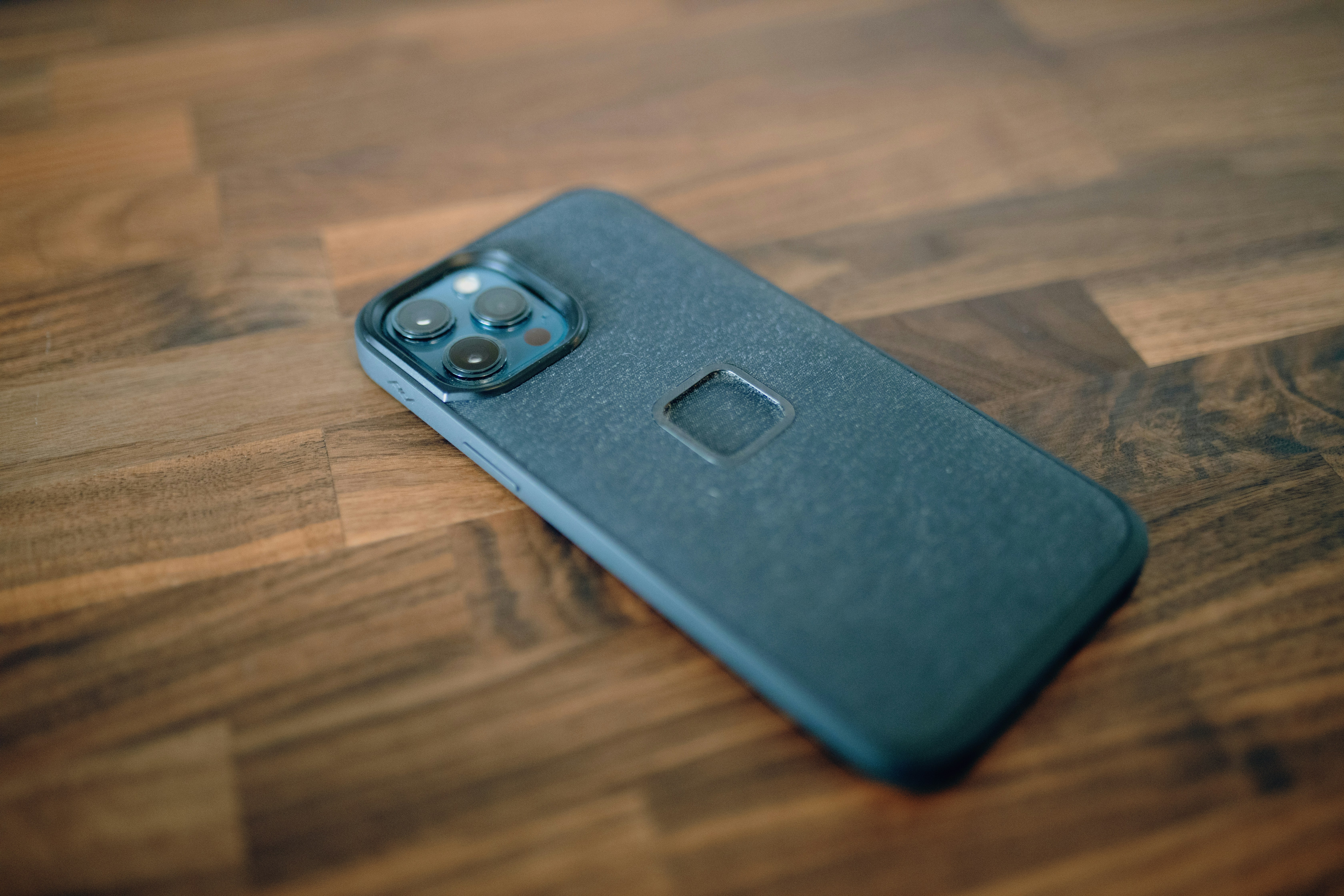 Smartphone resting on a wooden surface, showcasing its sleek design and camera features.