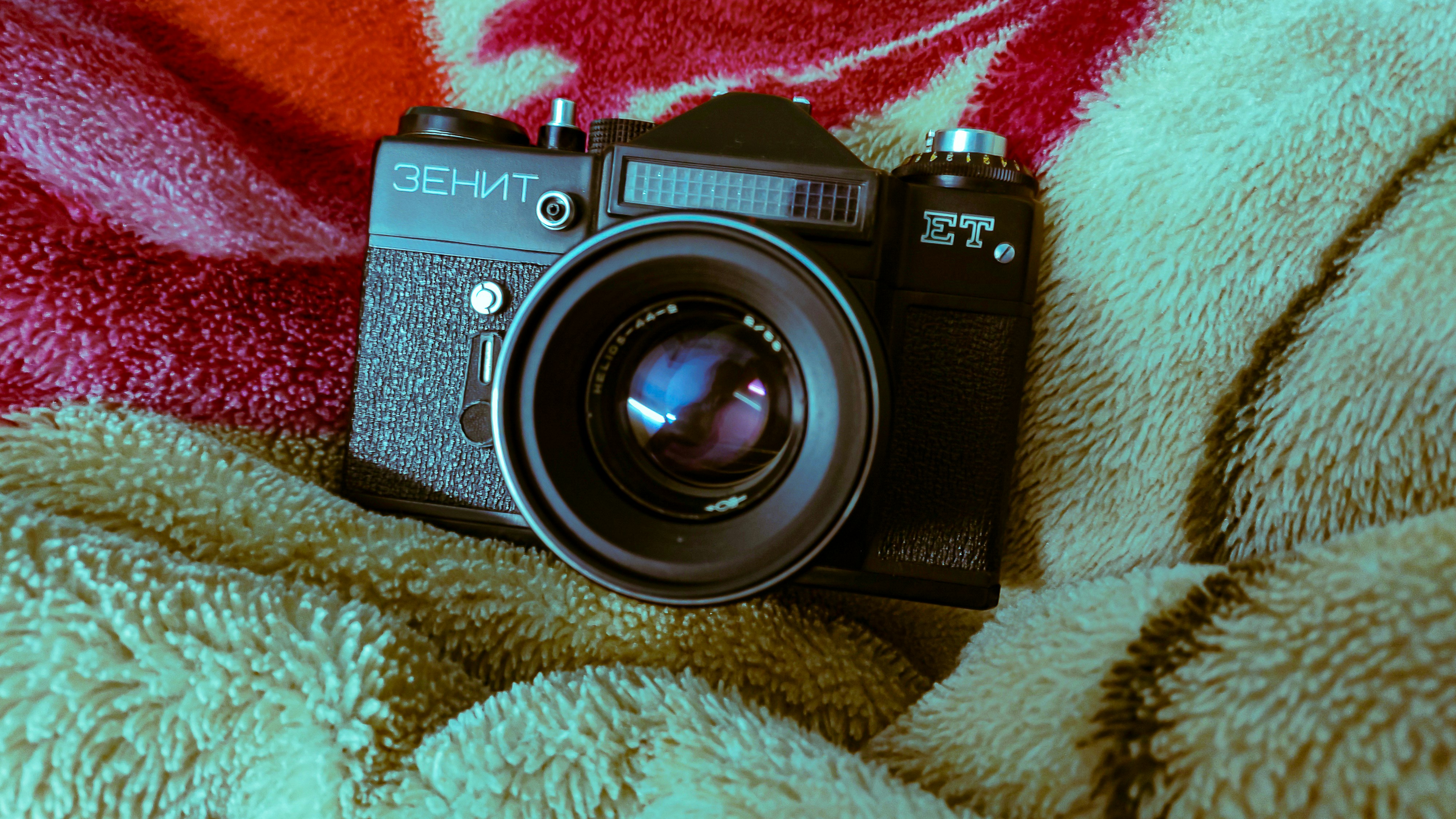 Zenit ET camera resting on a soft blanket, showcasing its classic design and intricate lens details.