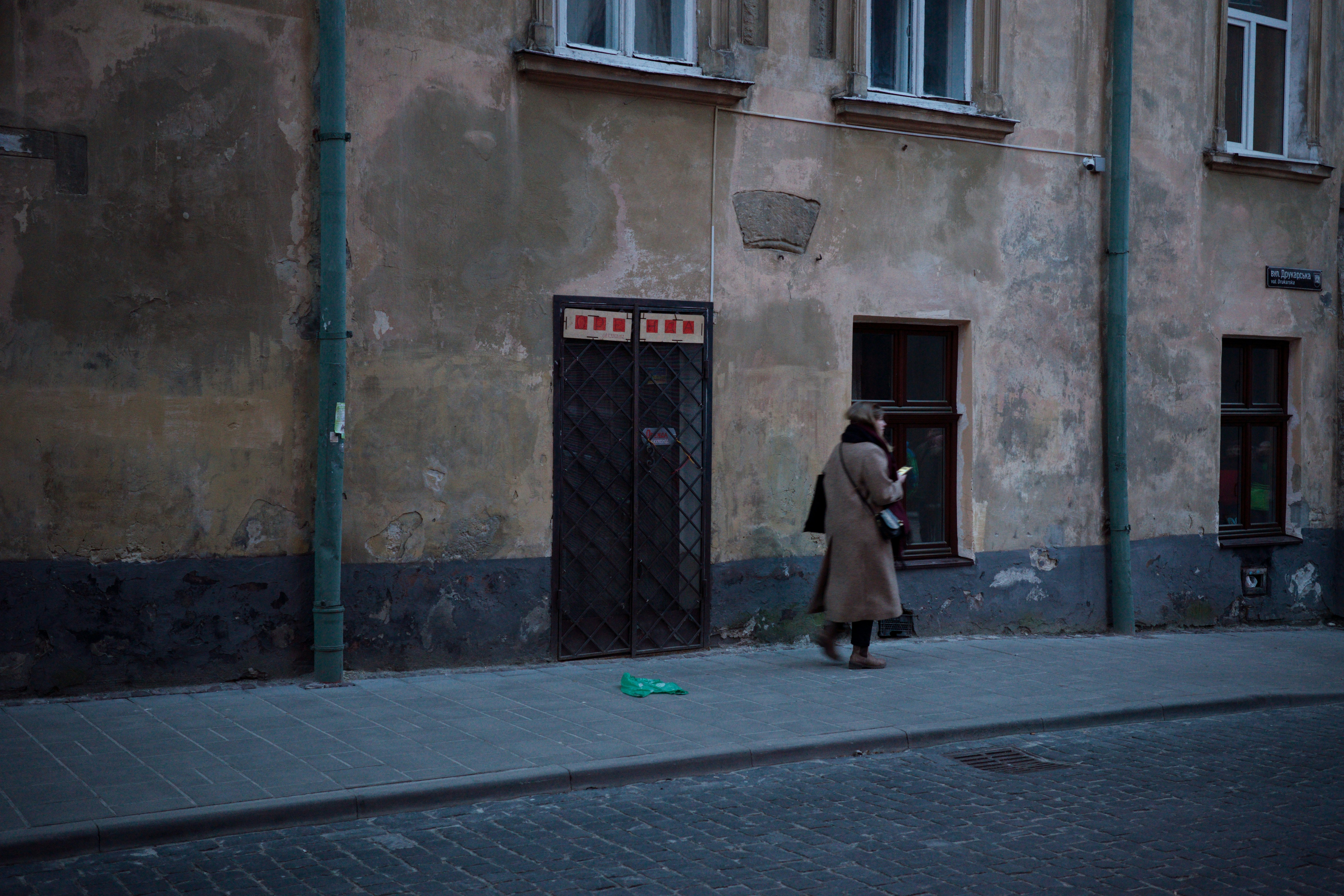 a woman walking down a street past a tall building