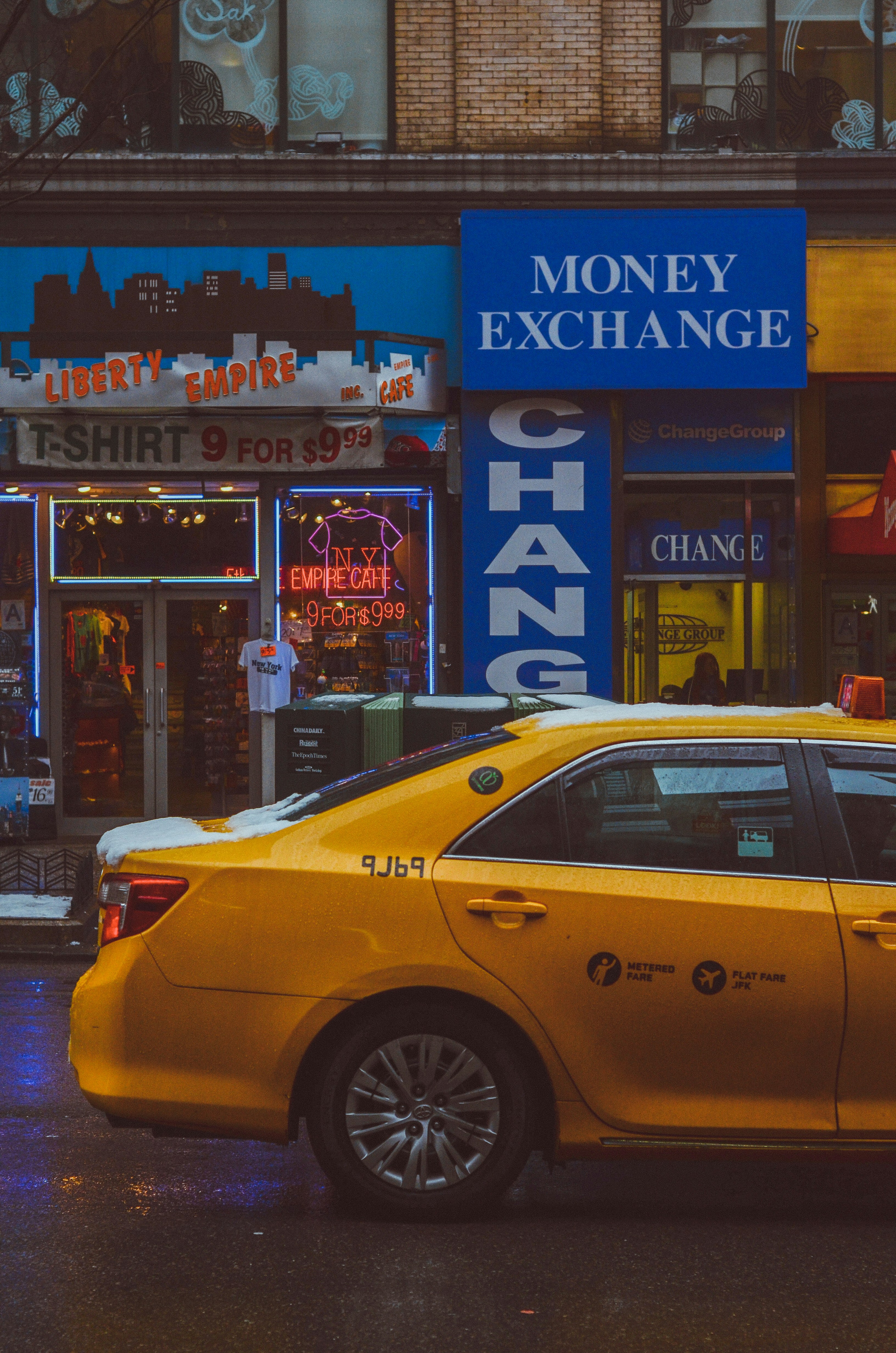 Neon Street Taxi: A Yellow Cab Anchors a Blue Money Exchange