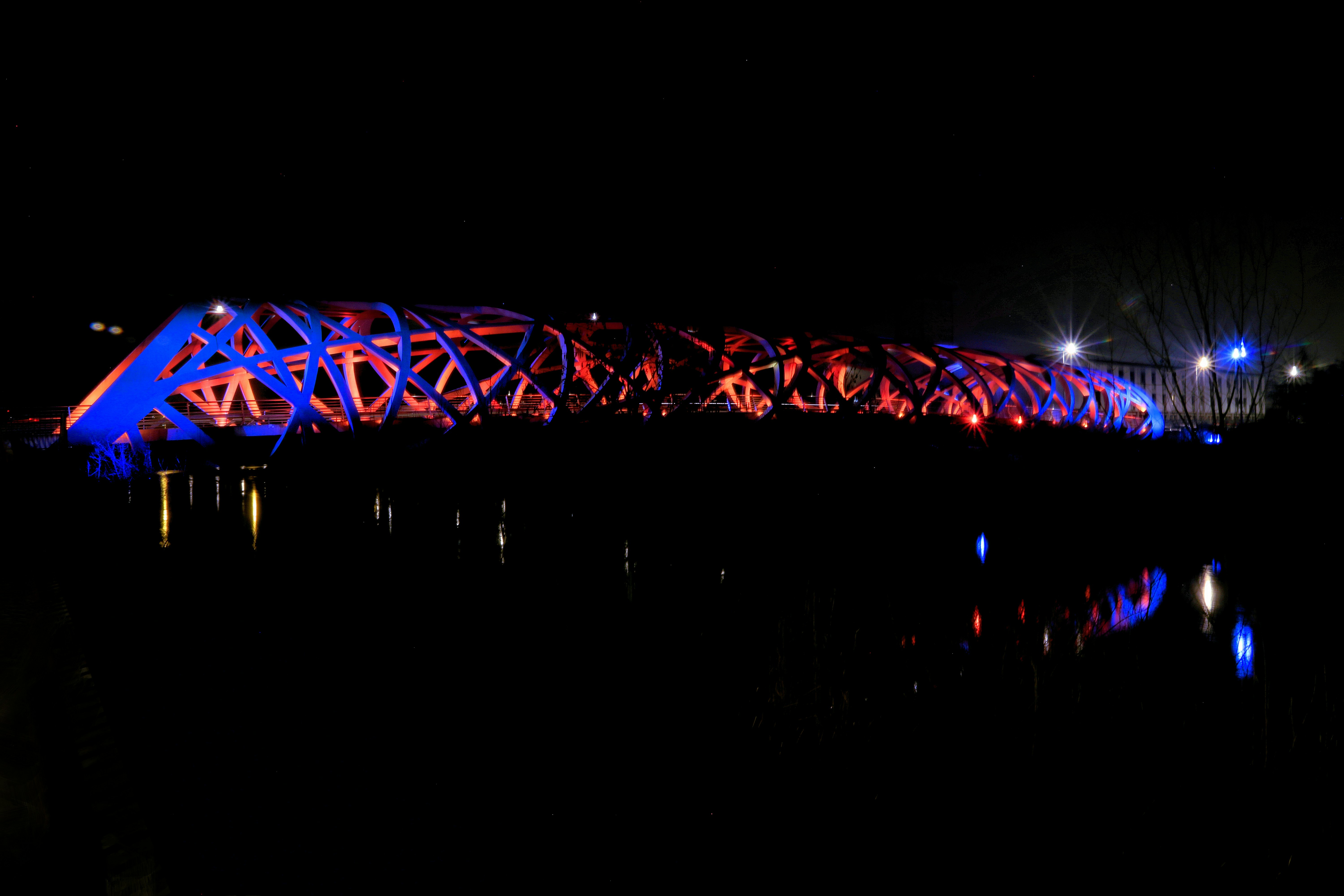 A lit up bridge over a body of water at night photo – Free Suisse Image ...