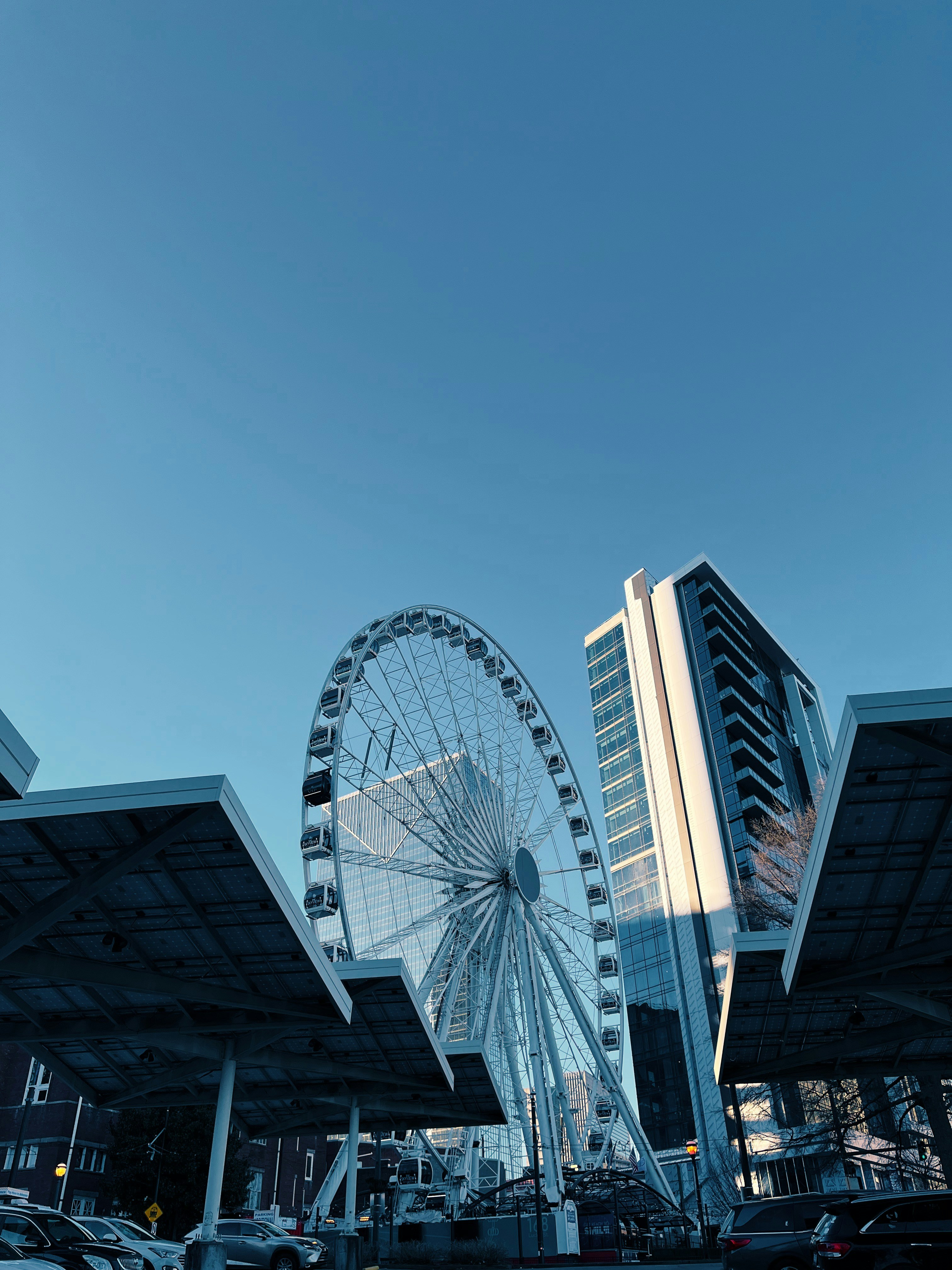 A large ferris wheel sitting next to a tall building photo – Free ...