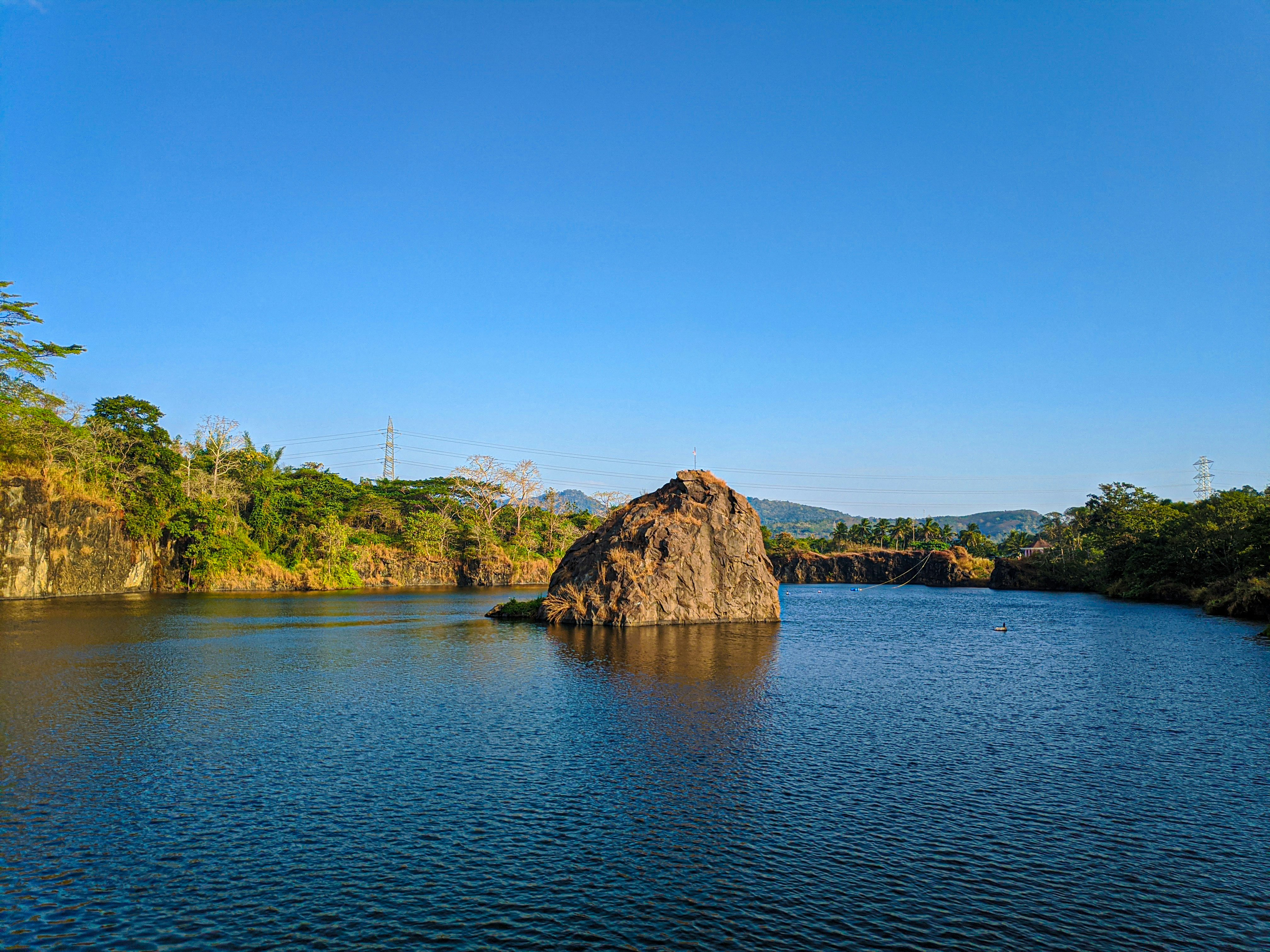 Midday Calm: A Lone Rock Rising from a Serene Reservoir