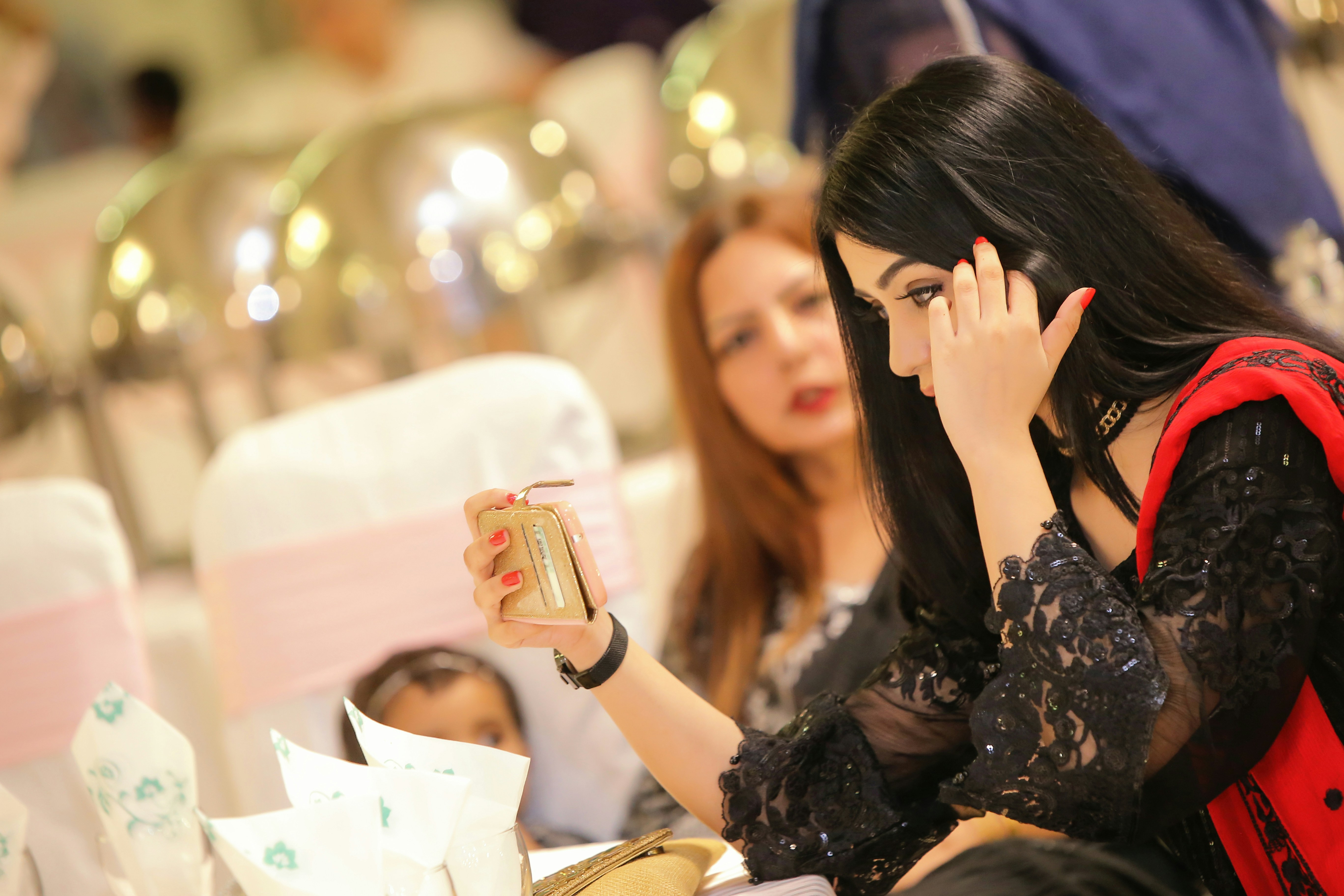 Two women engaged in a lively discussion at an indoor event with elegant decor.