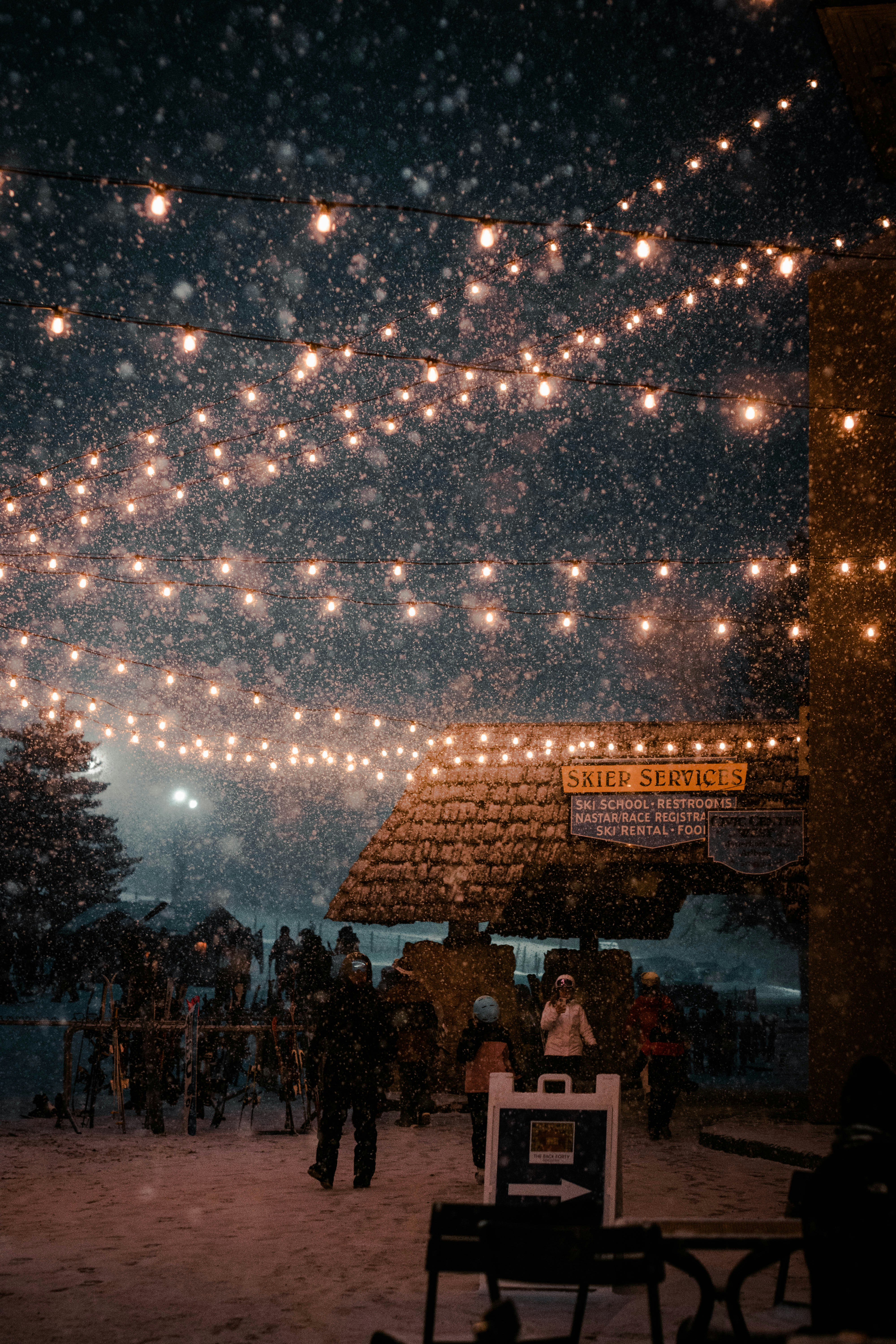Snowlit Night Under String Lights at a Skier Services Booth