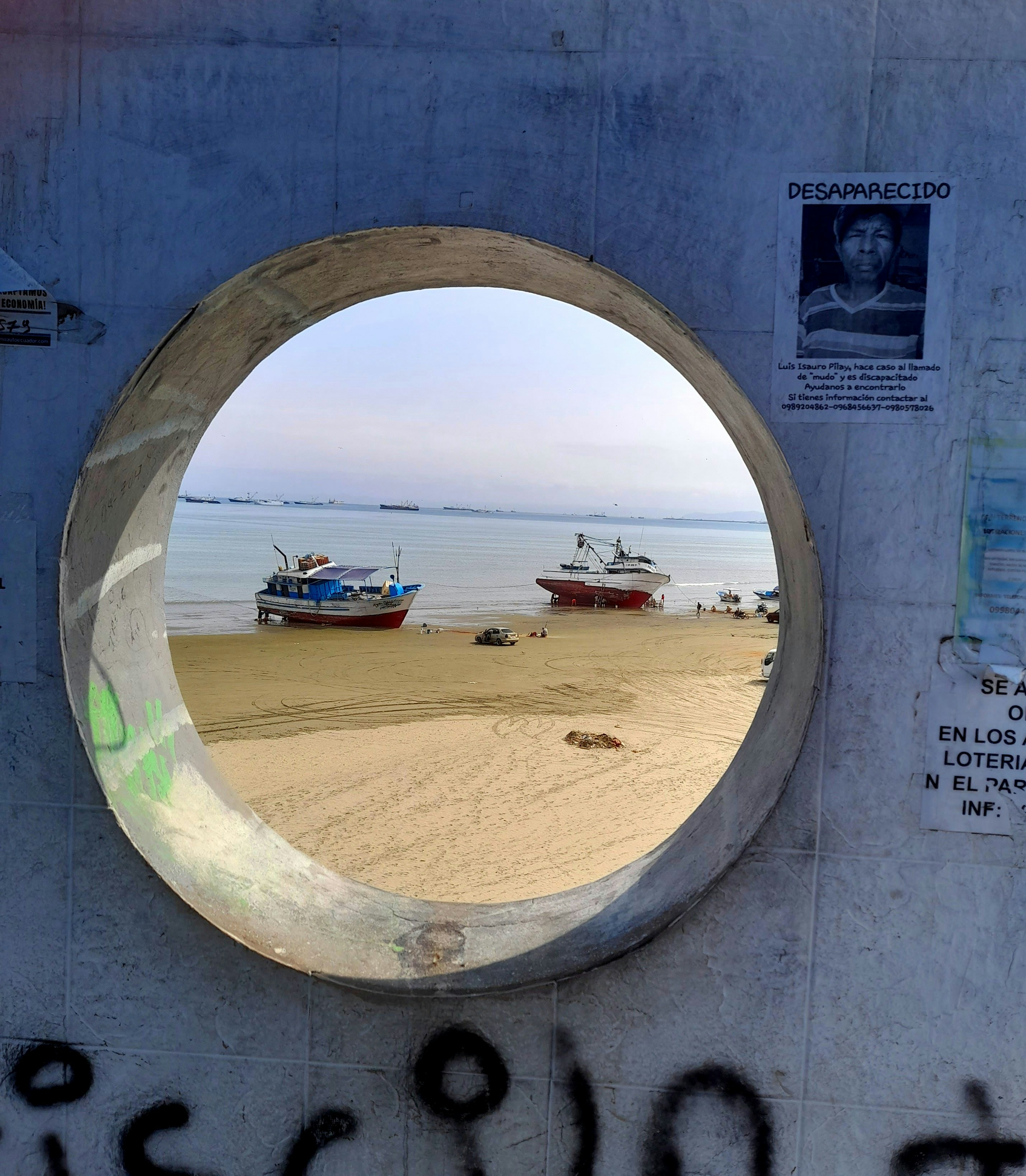 Porthole in pedestrian overpass on Malecon in Manta, Ecuador. | a round window on the side of a wall