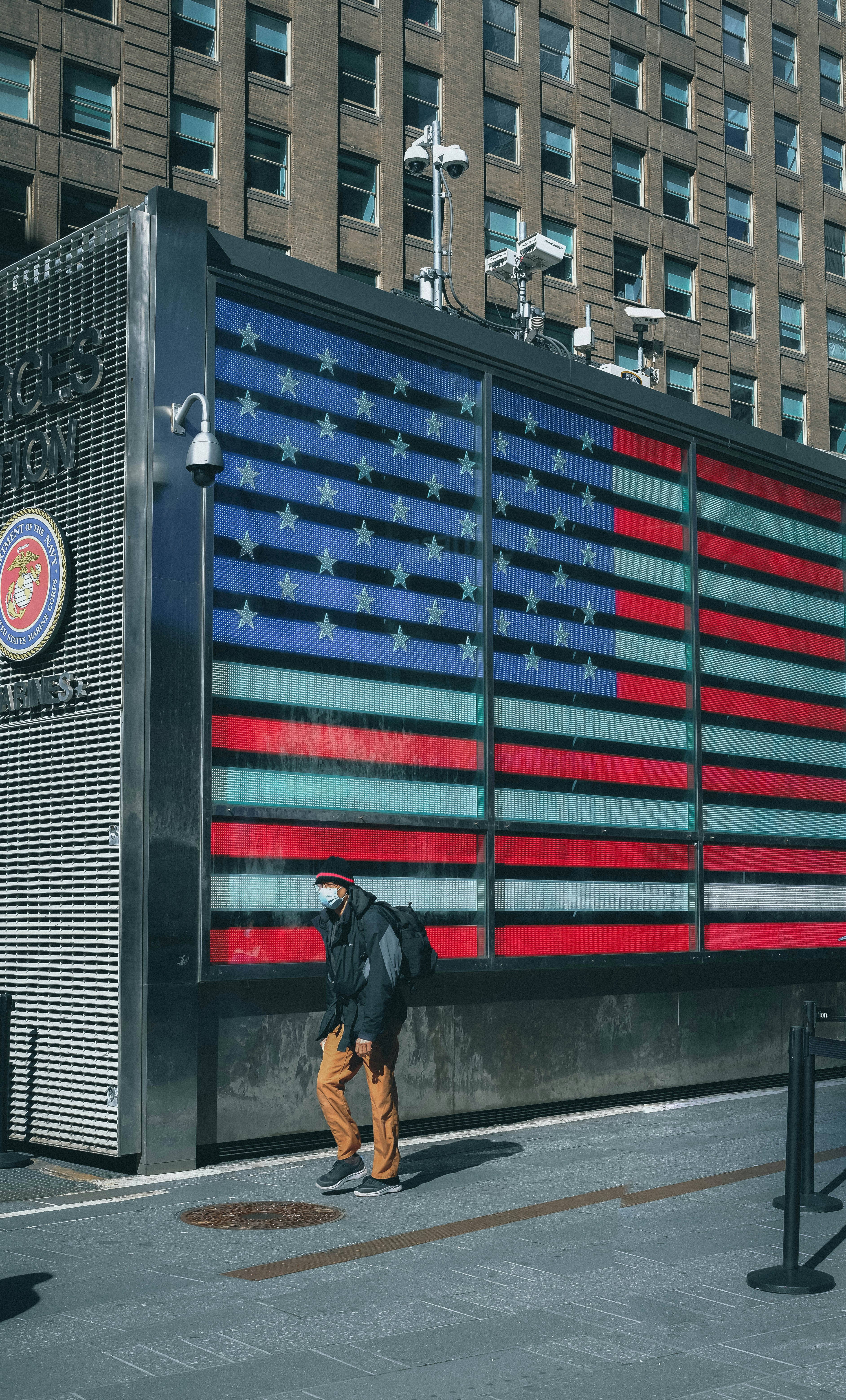 a man walking down a street past a large american flag