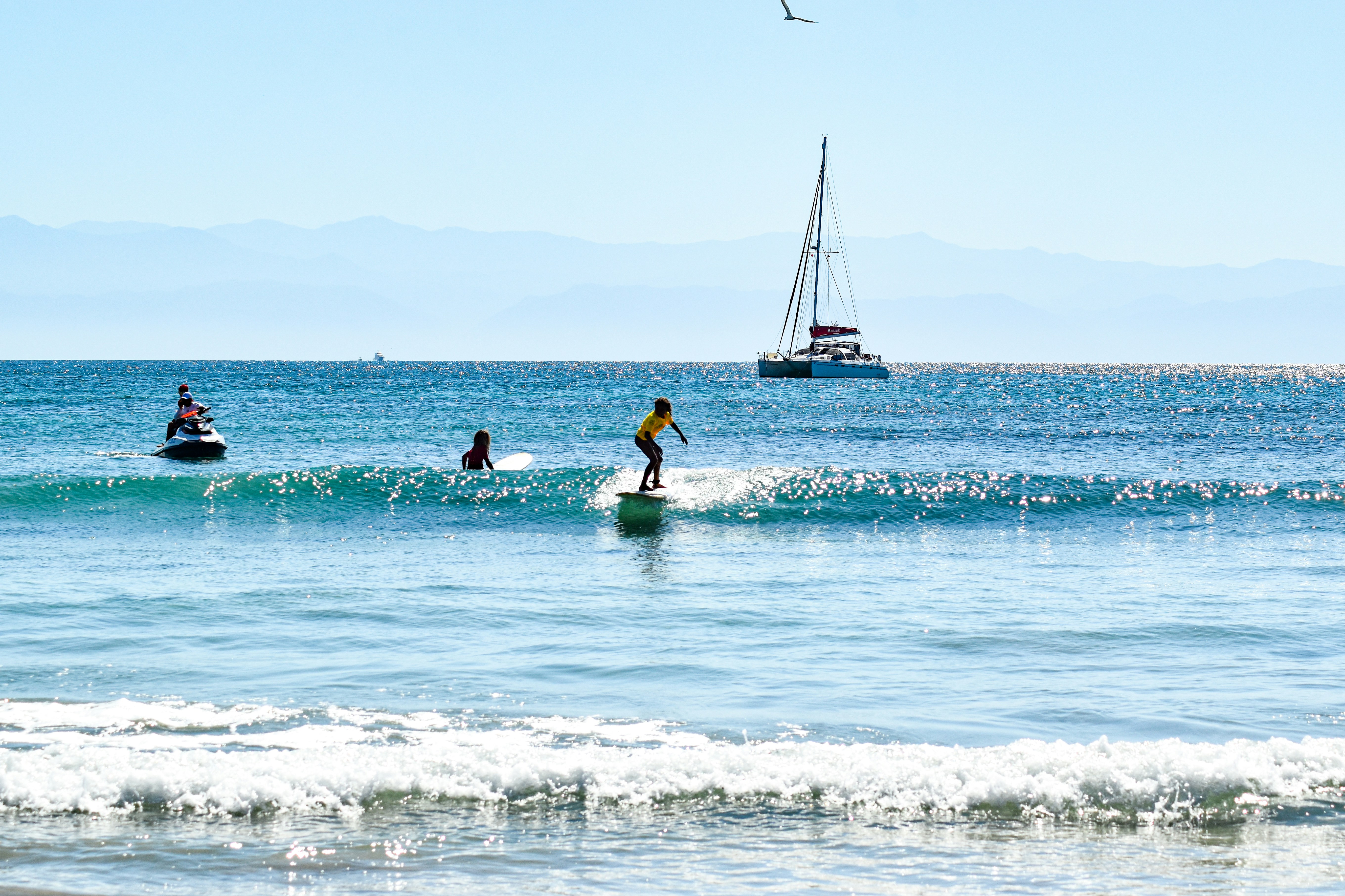 A group of people riding surfboards on top of a wave photo – Free Surf ...