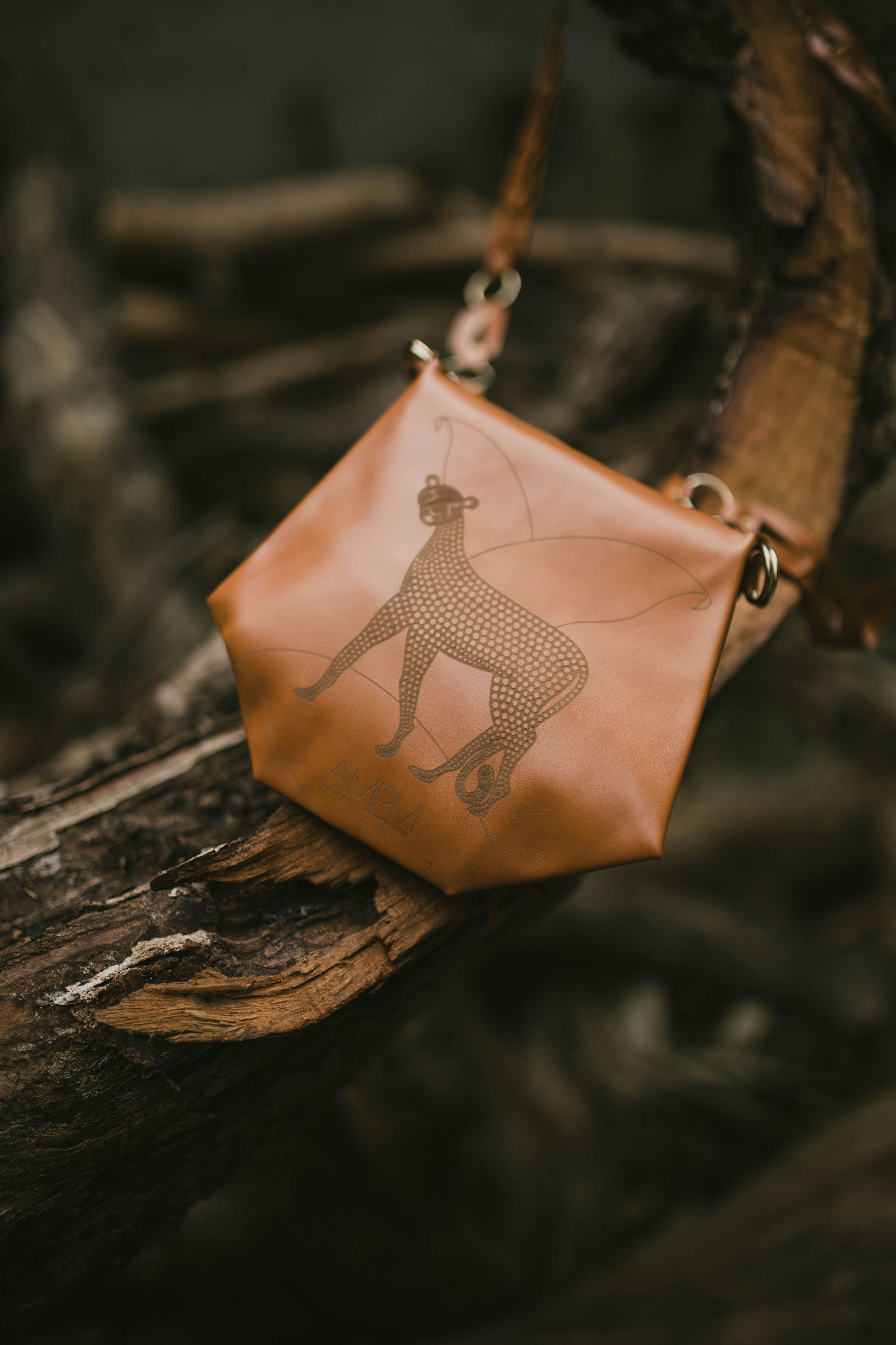 Leather hexagonal handbag with a geometric animal motif perched on a mossy branch