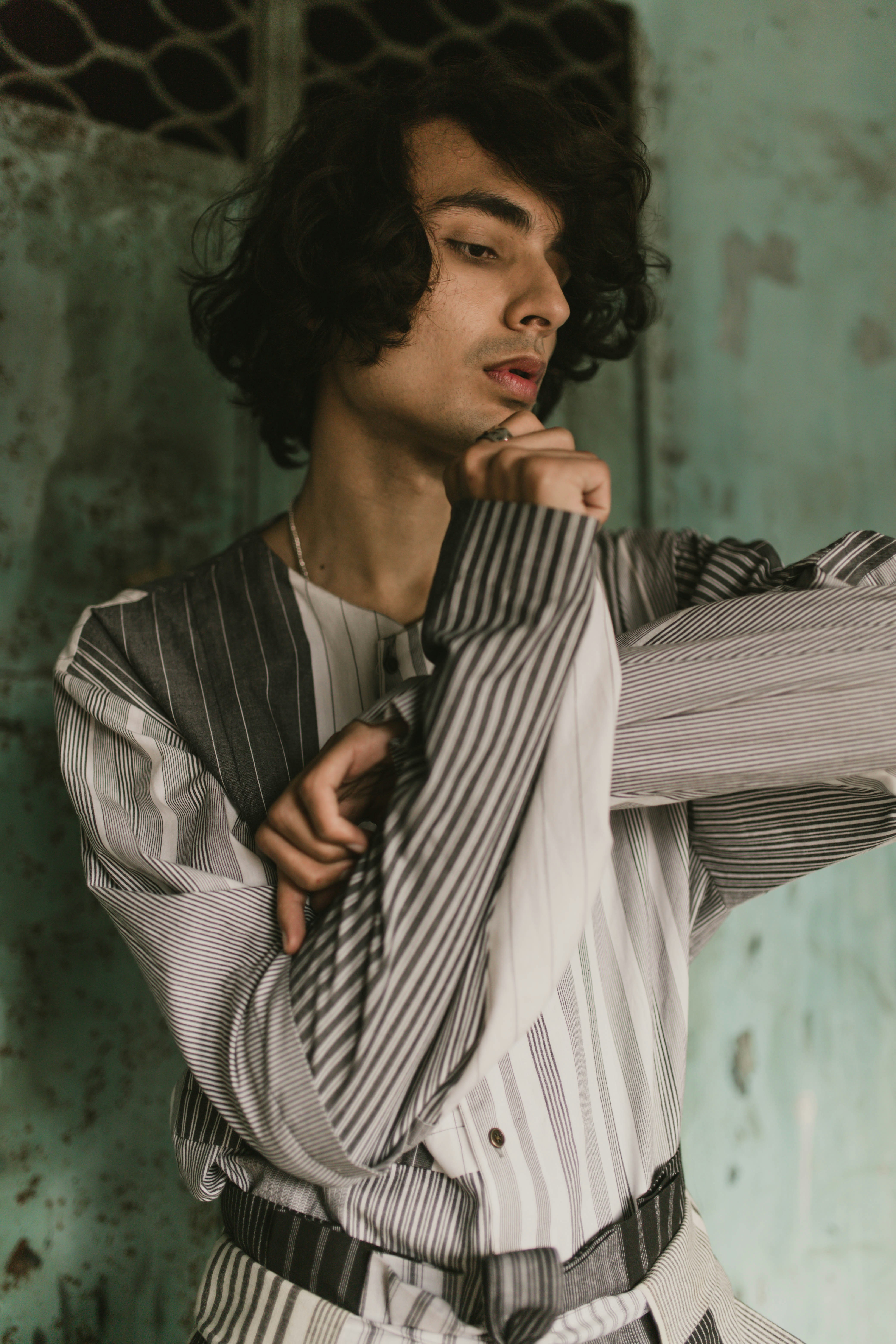 Stripes and Stillness: Portrait Against a Weathered Mint Wall