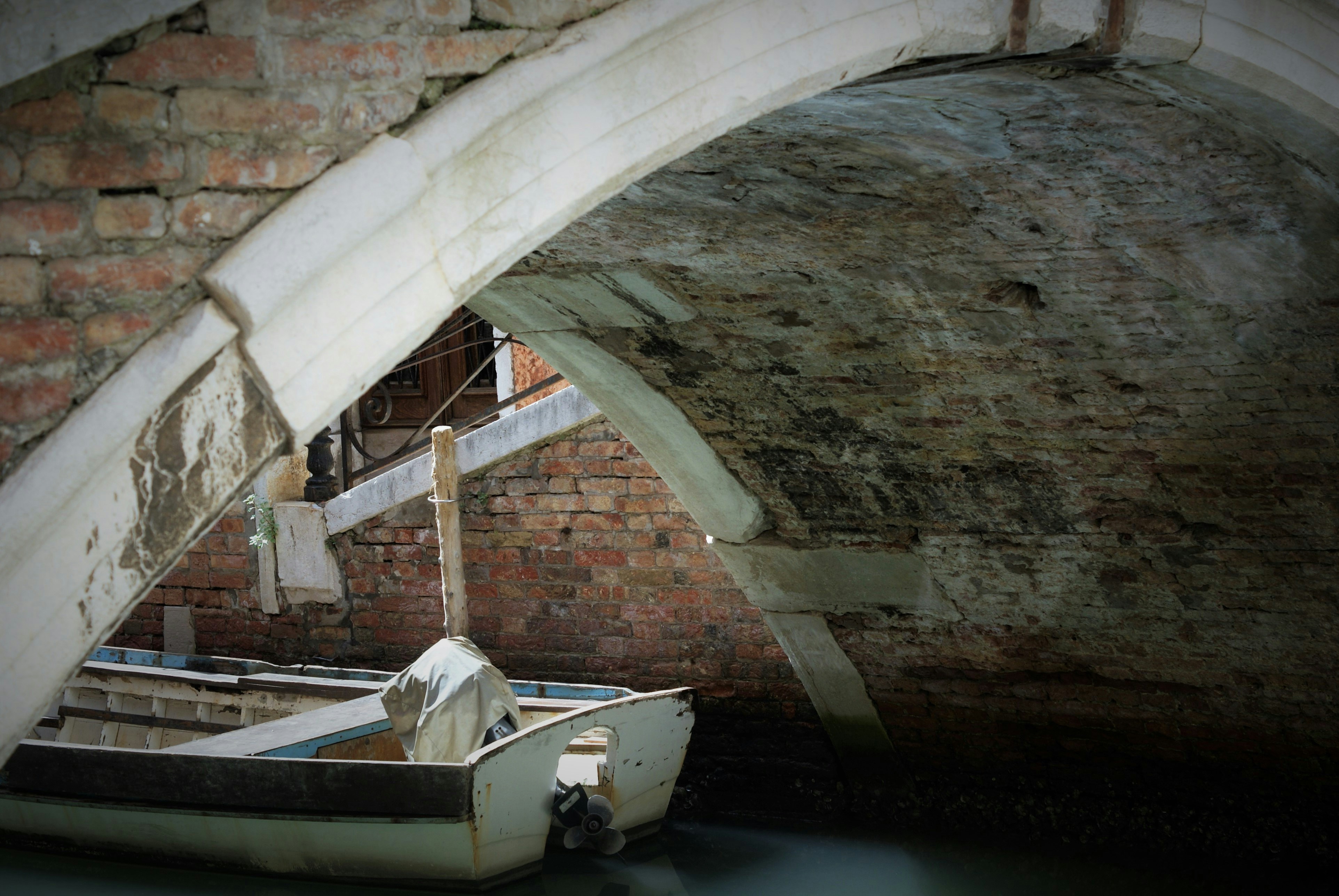 a small boat in a canal under a bridge