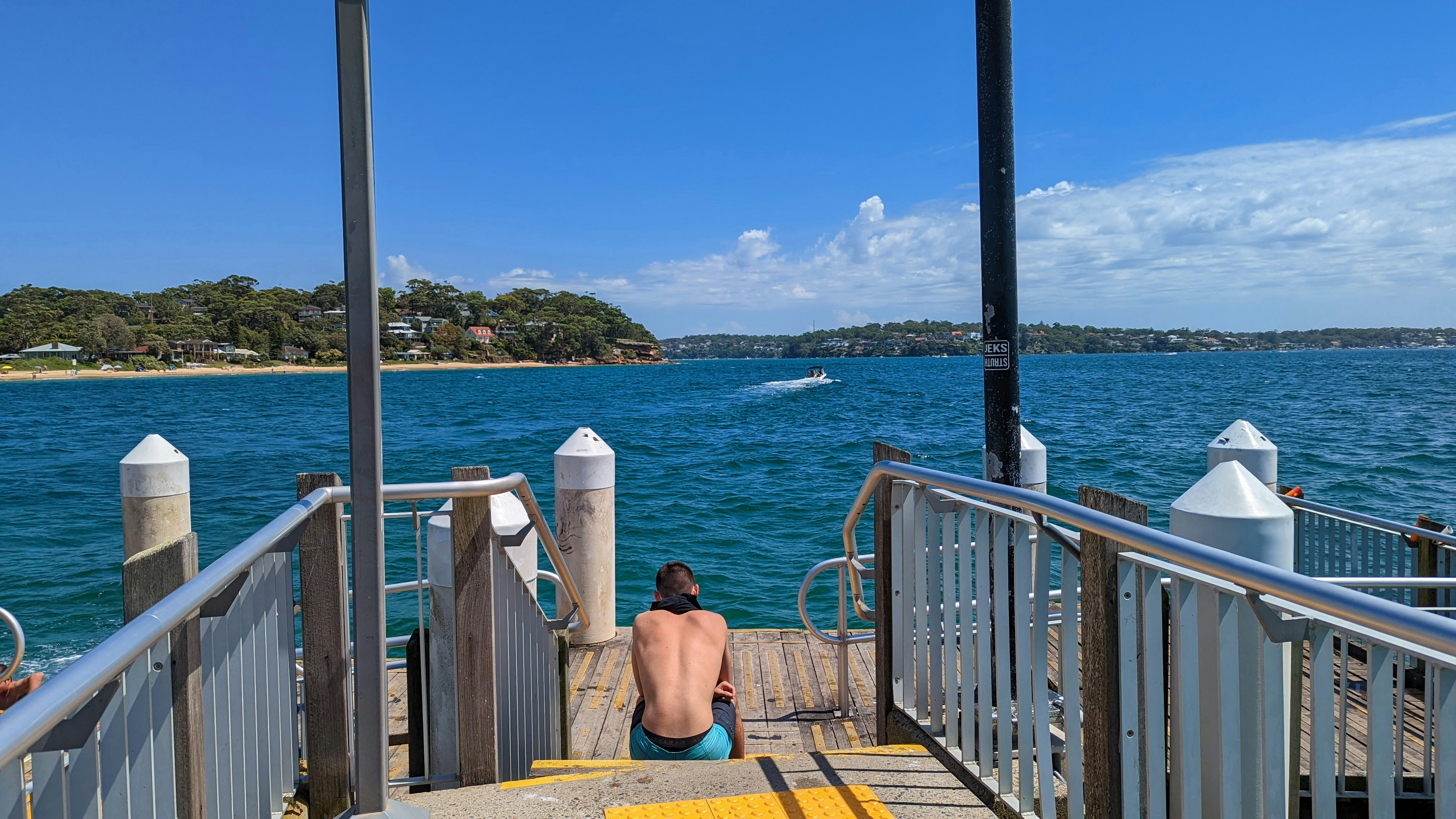 Sunlit Pier Reverie: A Seated Figure Gazing at the Wide Blue Sea