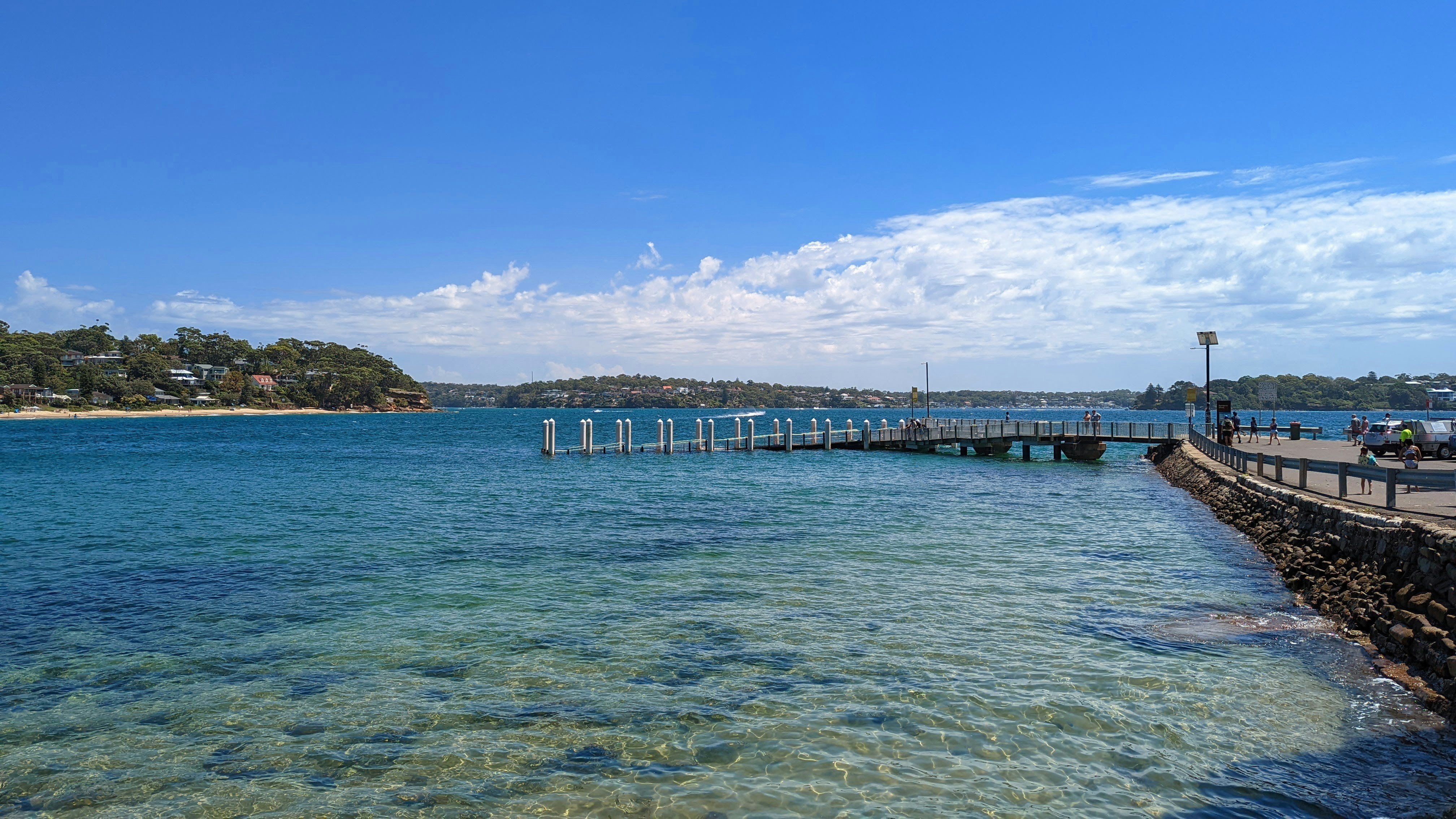 Azure Promenade: Sunlit Pier Over Calm Coastal Waters