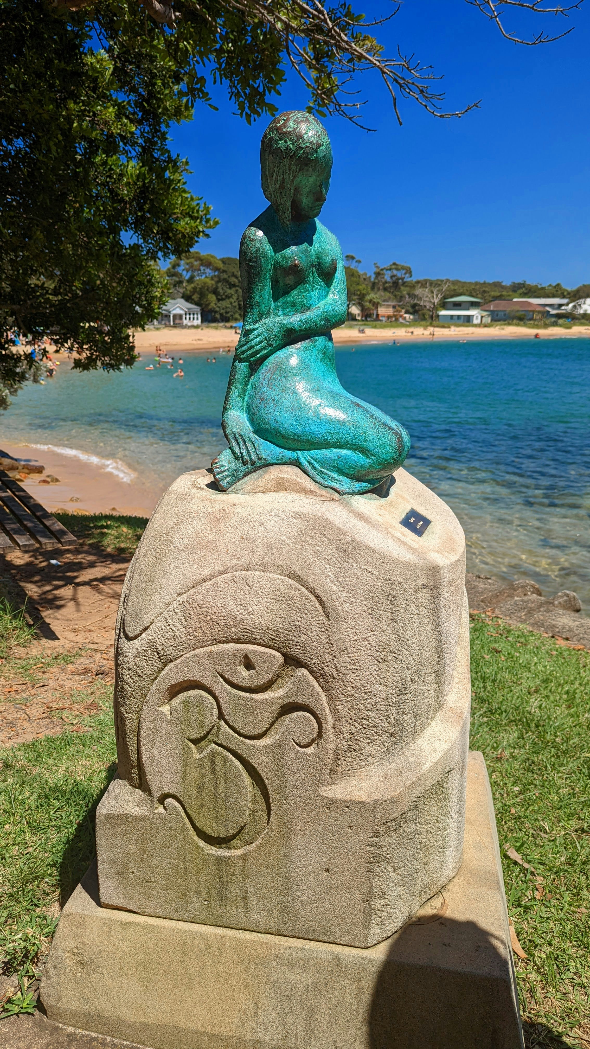 Verdant Mermaid Sculpture Guards a Sunlit Bay