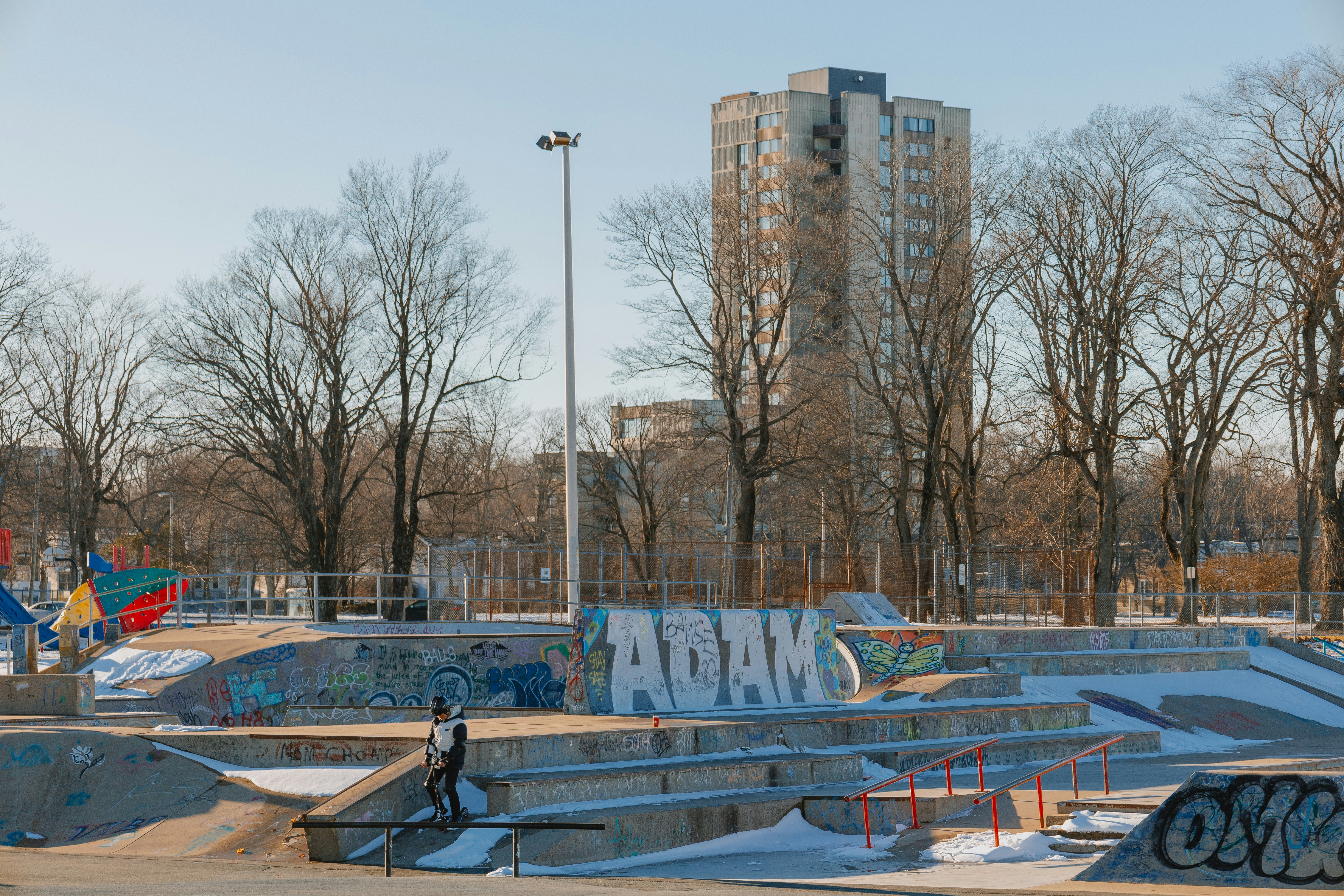 Skateboarder navigating through a vibrant skate park adorned with colorful graffiti and surrounded by winter trees.