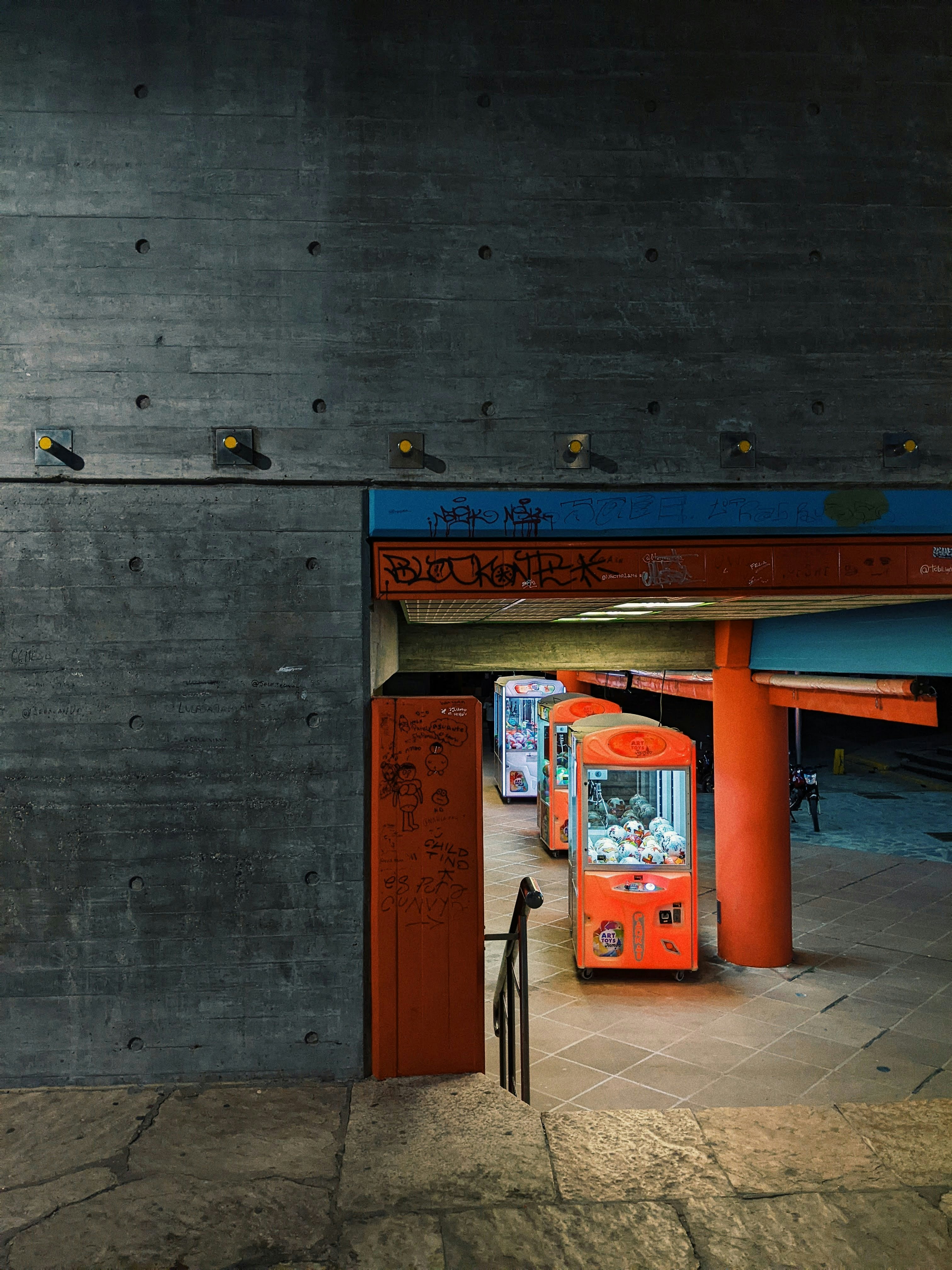 an orange and blue bus parked in a parking garage