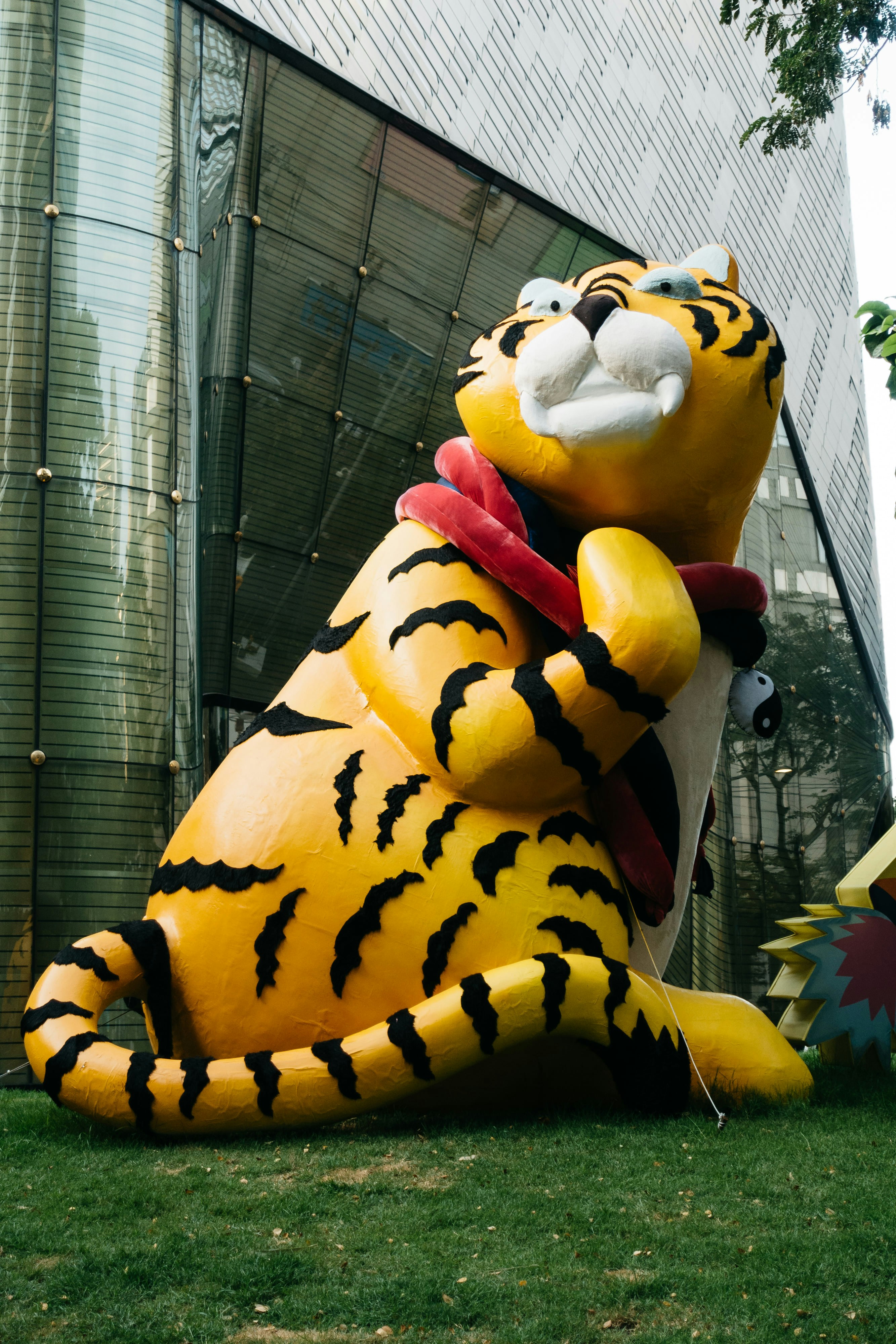 A large inflatable tiger sitting on top of a lush green field photo ...