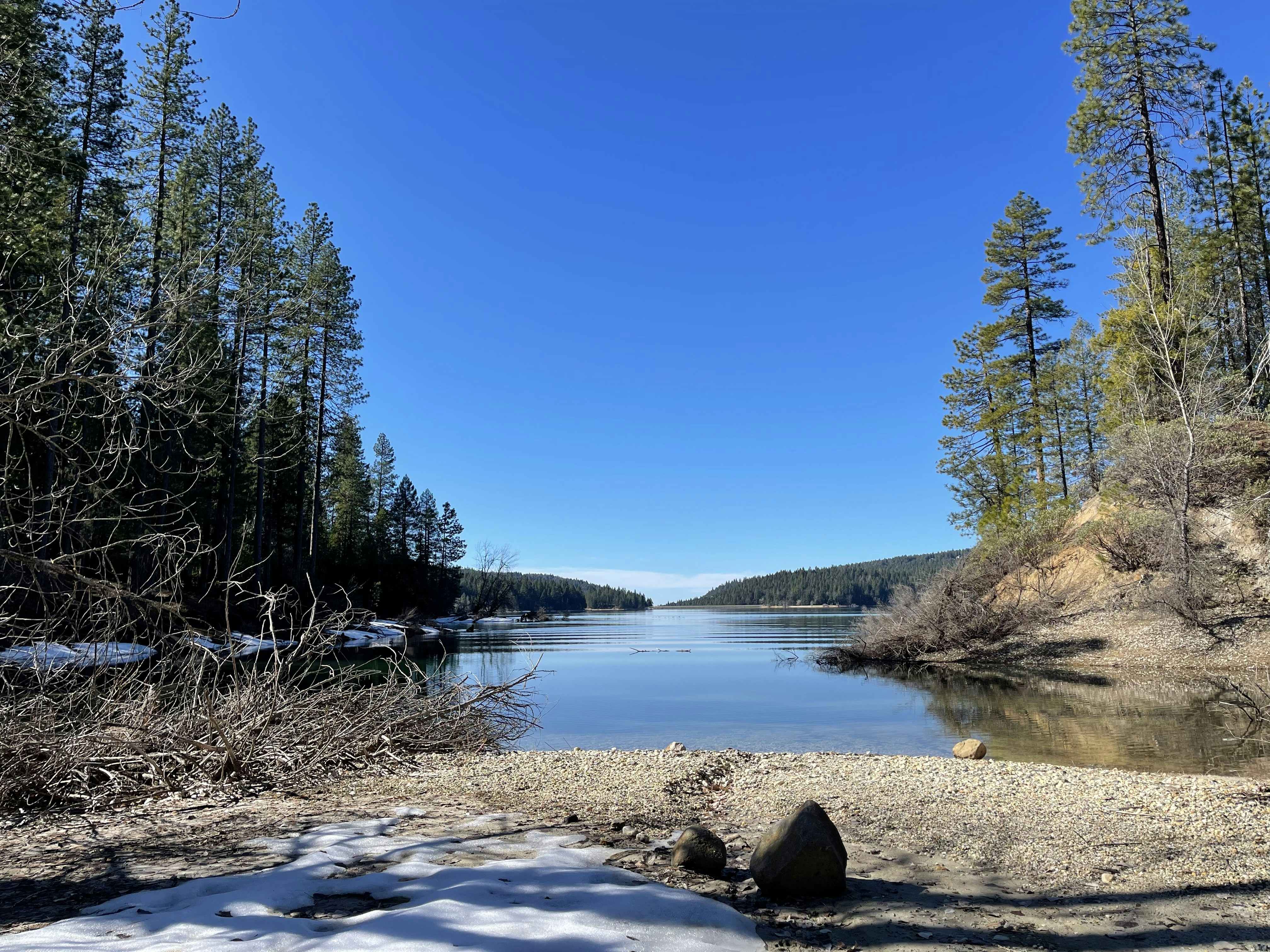 A lake surrounded by trees and snow covered ground photo – Free Nature ...