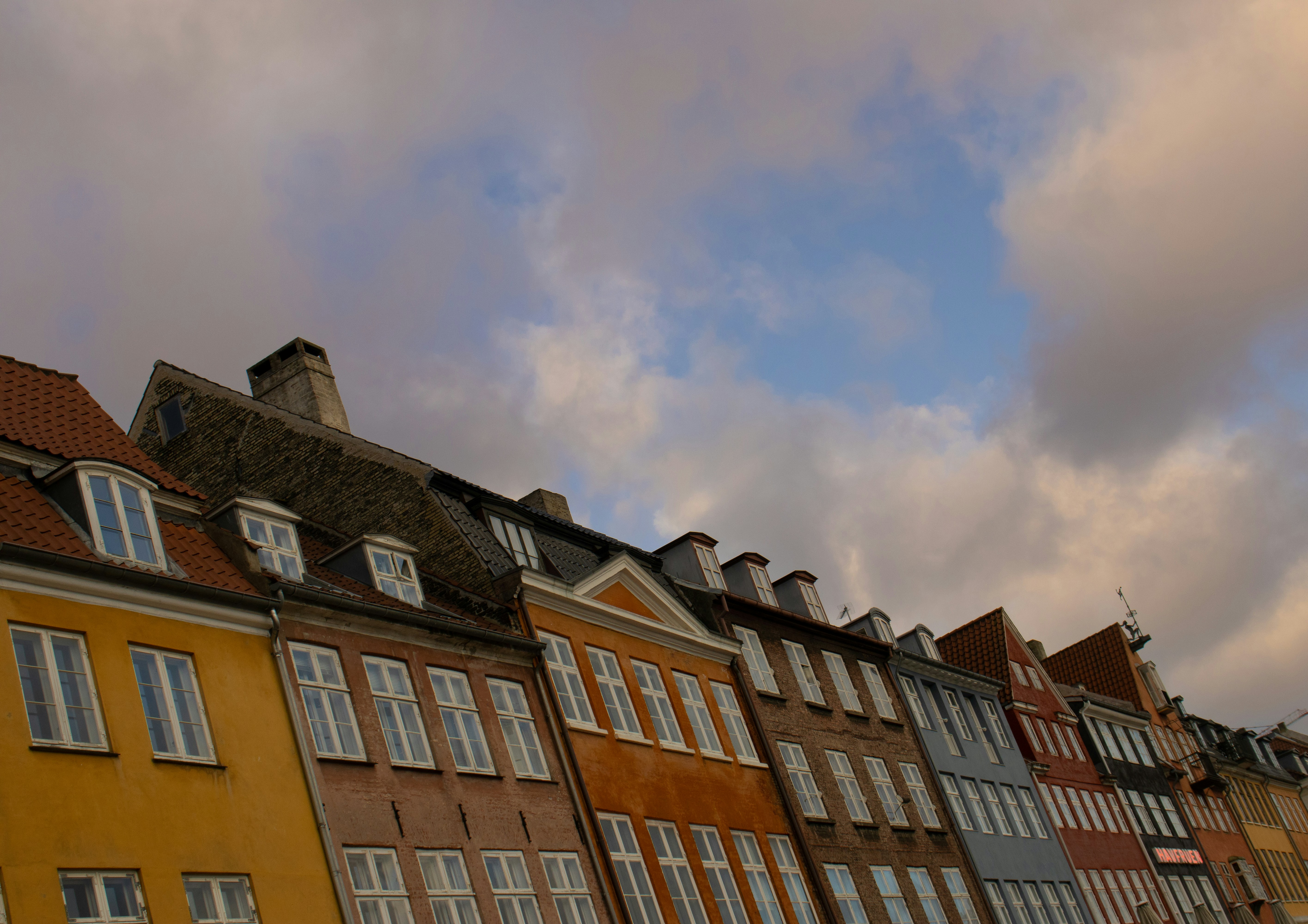 Colorful row of historic buildings under a cloudy sky, showcasing architectural diversity and charm.