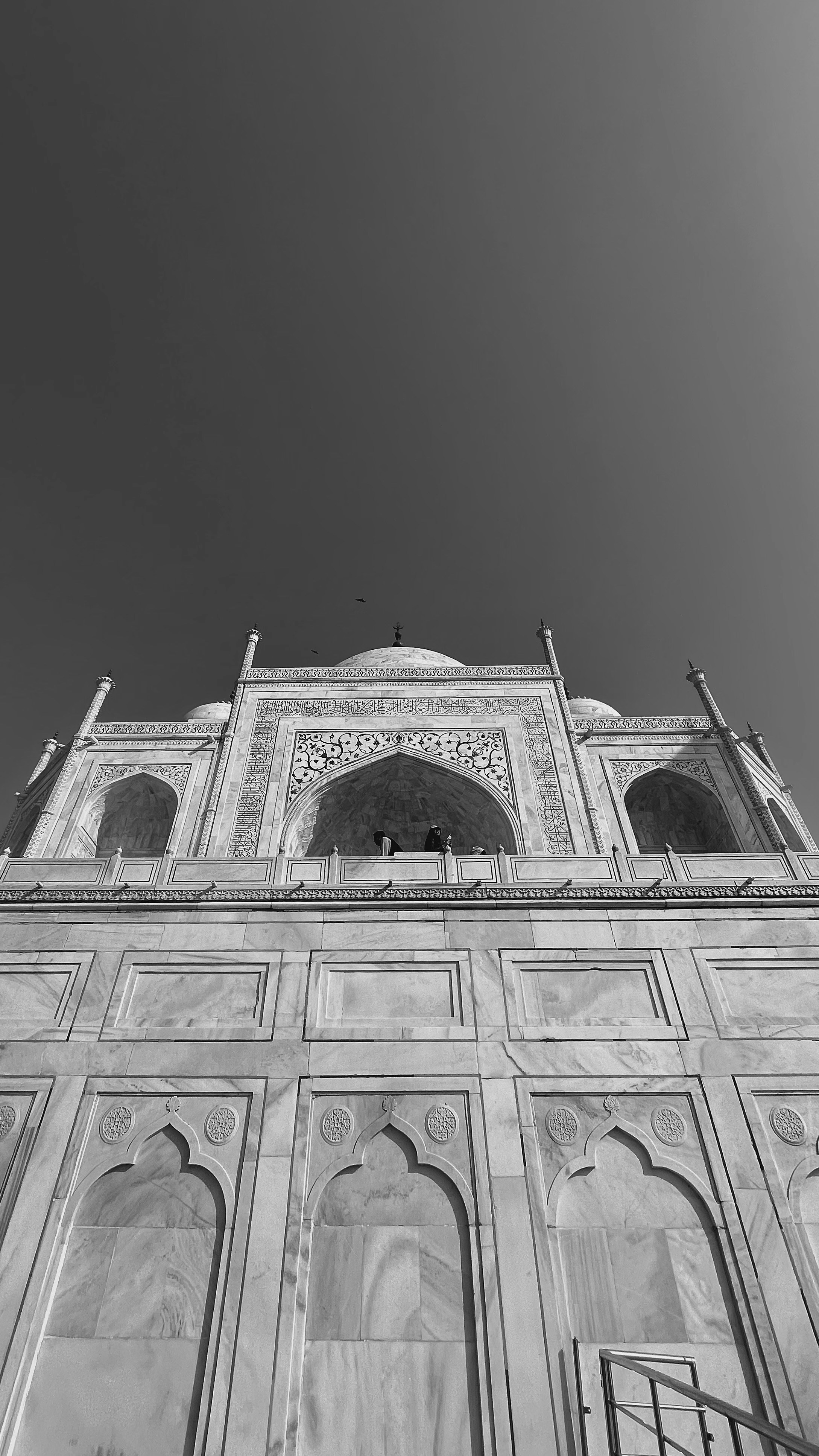 Intricate marble details of the Taj Mahal captured from a low angle, emphasizing its grandeur against a clear sky.