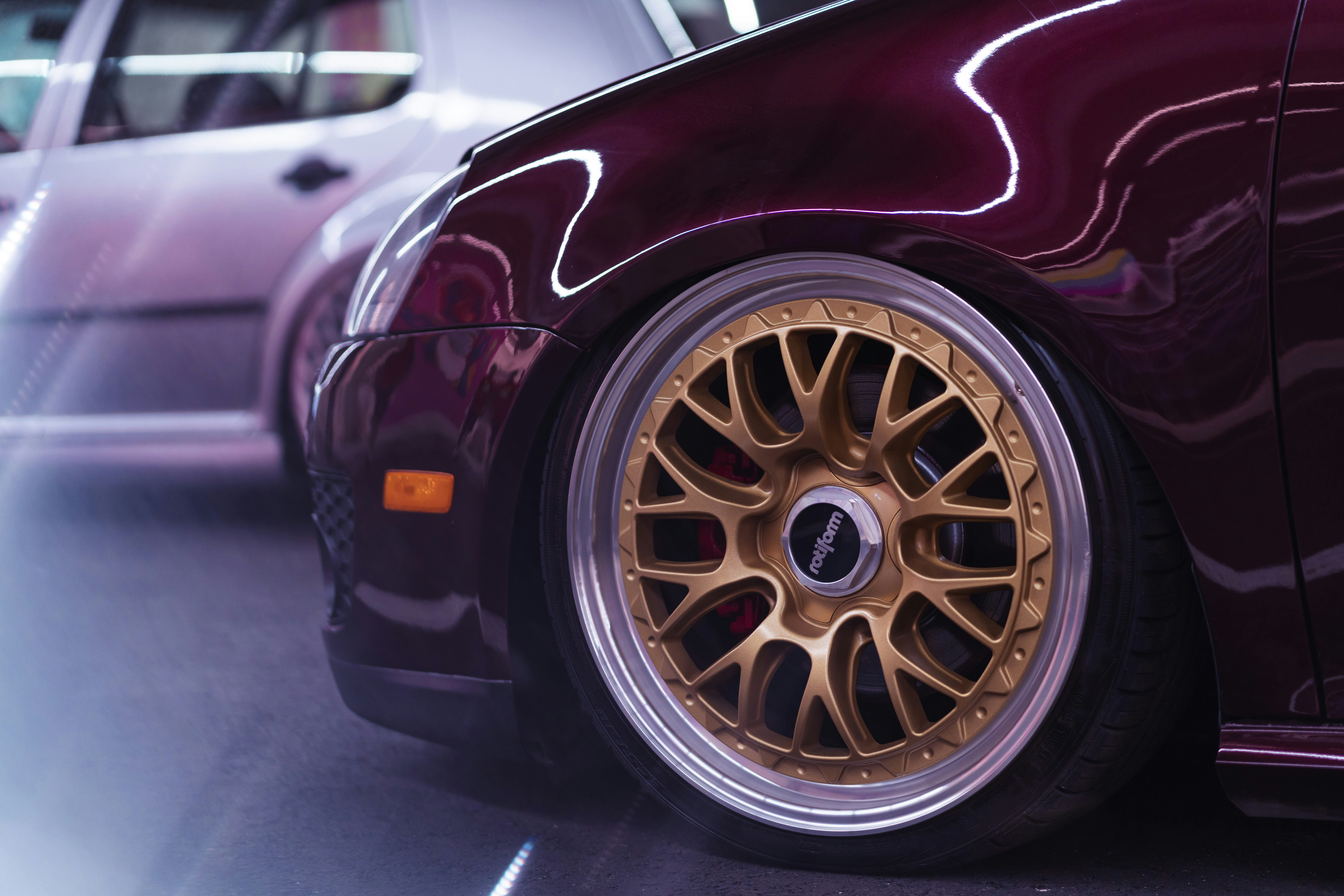 A maroon car with gold rims parked next to a white car photo – Free Usa ...
