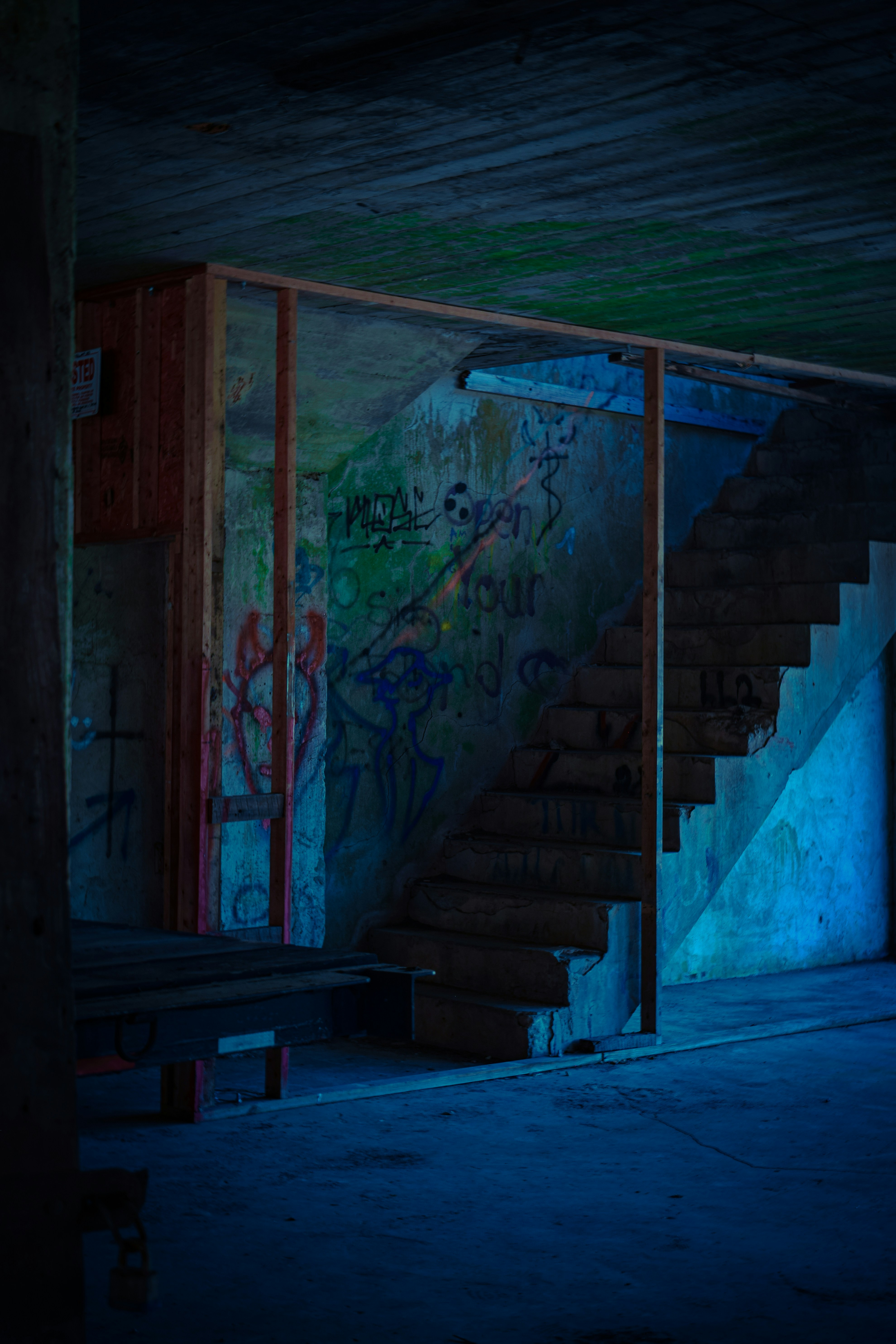 Dimly lit interior of an abandoned building showcasing a staircase adorned with graffiti. The atmosphere conveys a sense of neglect and mystery.