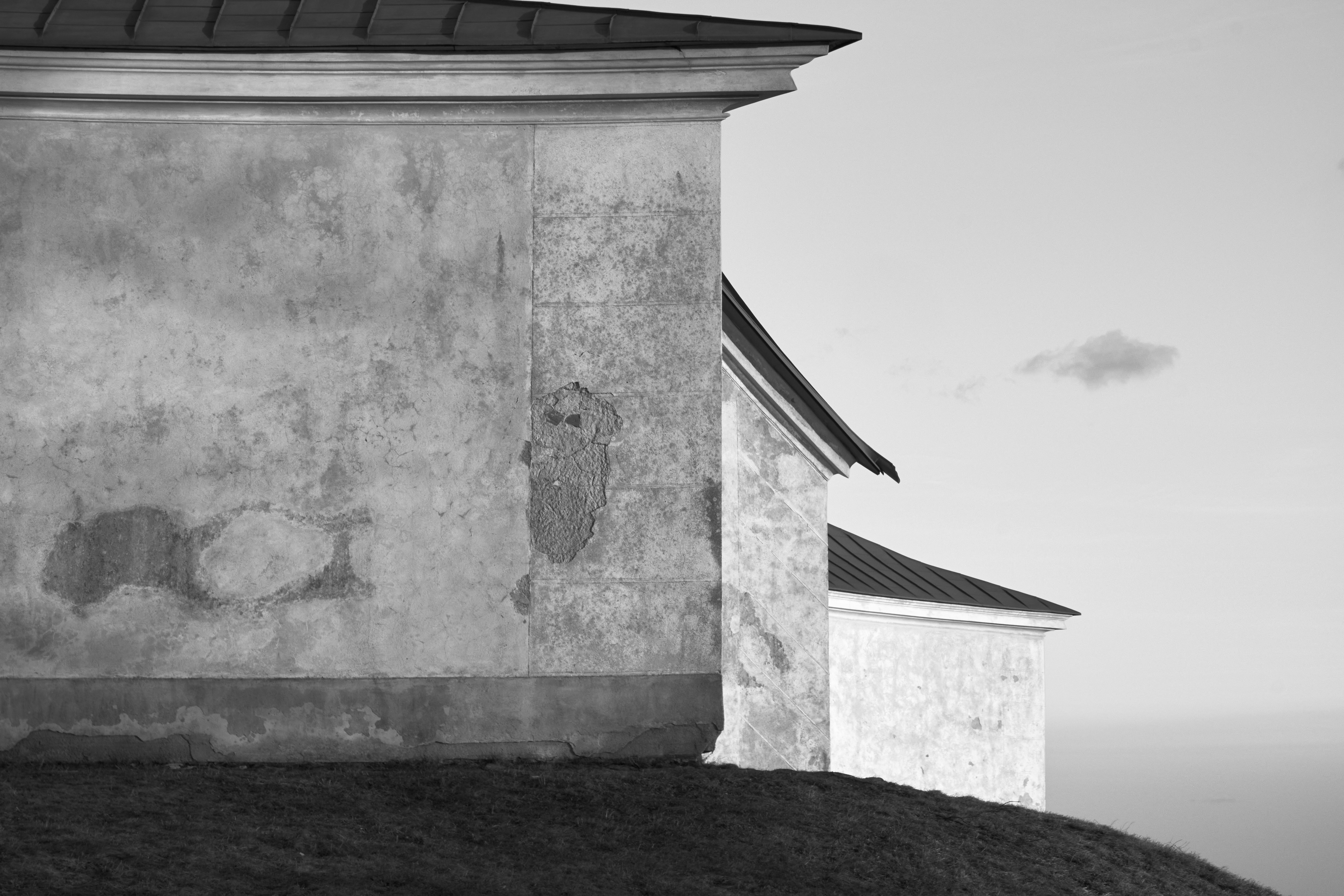 Weathered stone buildings with a sloping roof against a twilight sky.