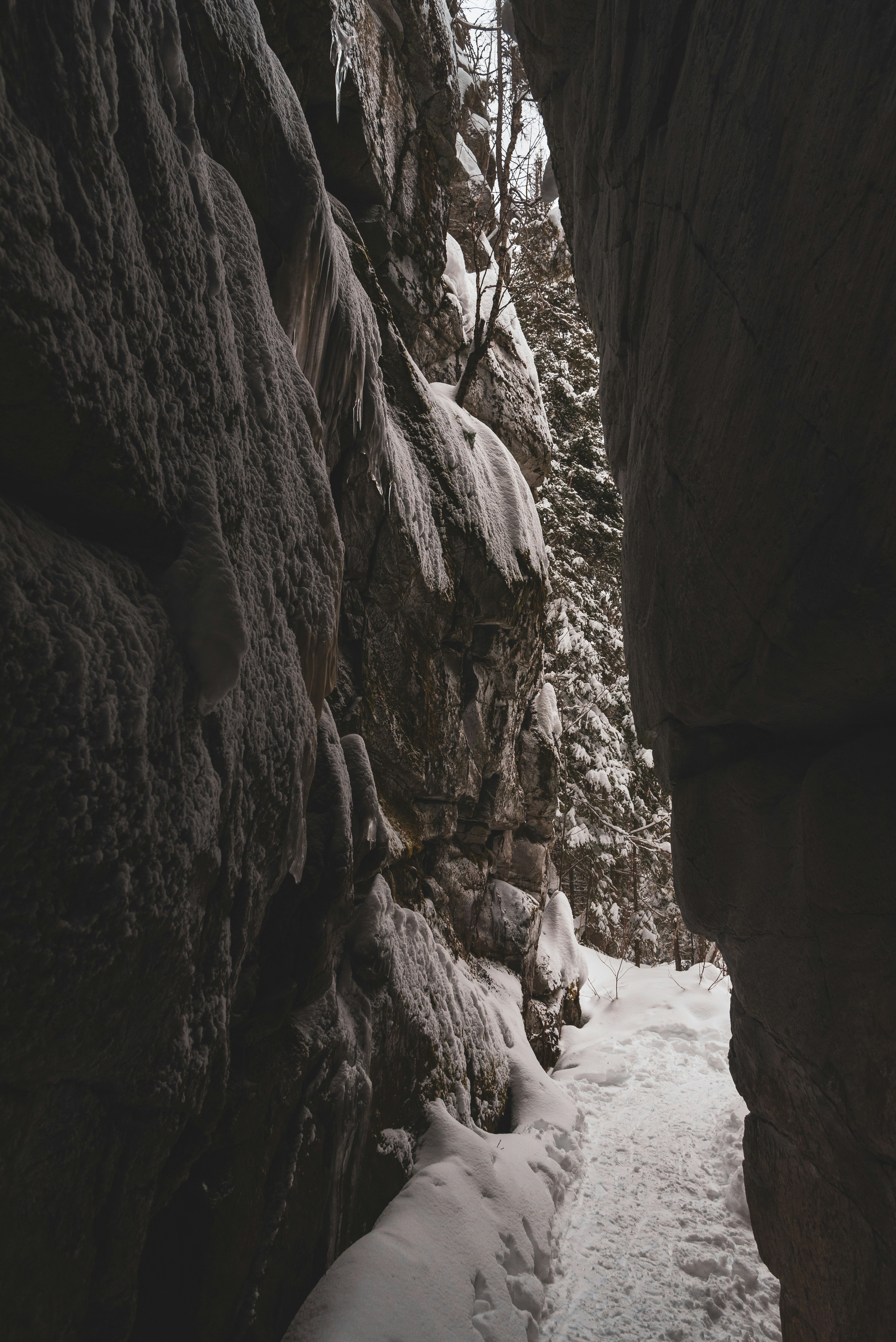A narrow path between two large rocks covered in snow photo – Free ...