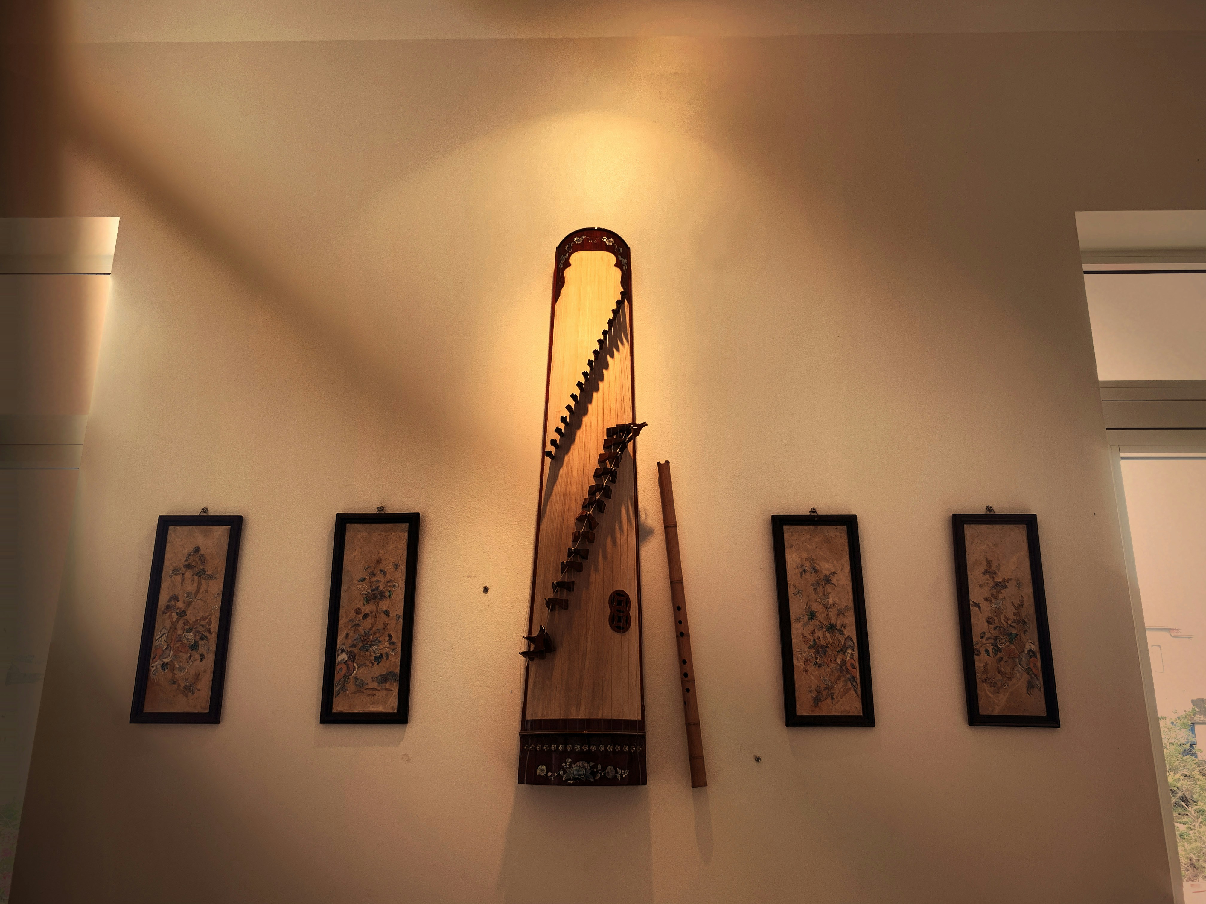 A musical instrument hanging on a wall next to four framed pictures ...