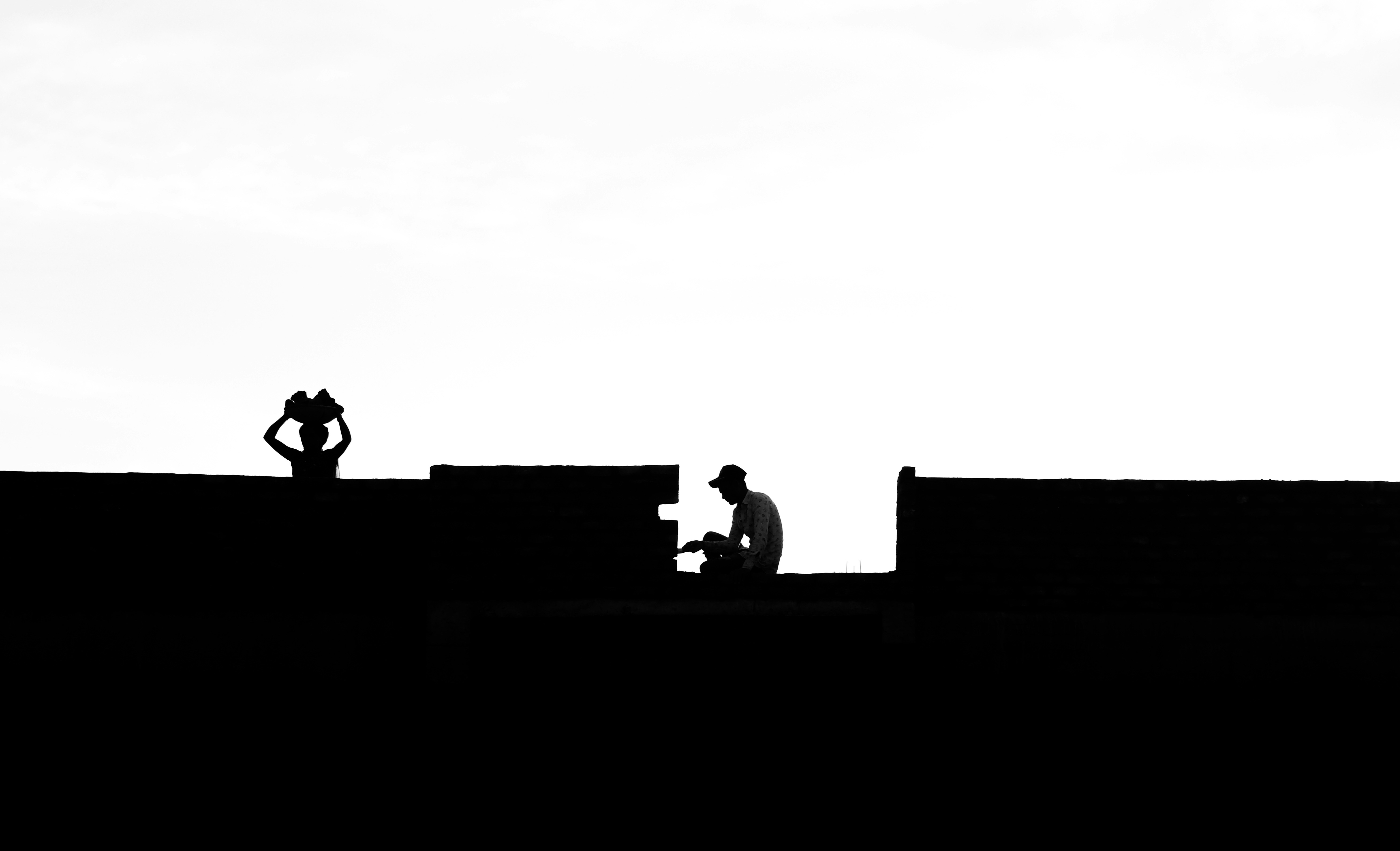Silhouetted figures on a rooftop against a bright sky.