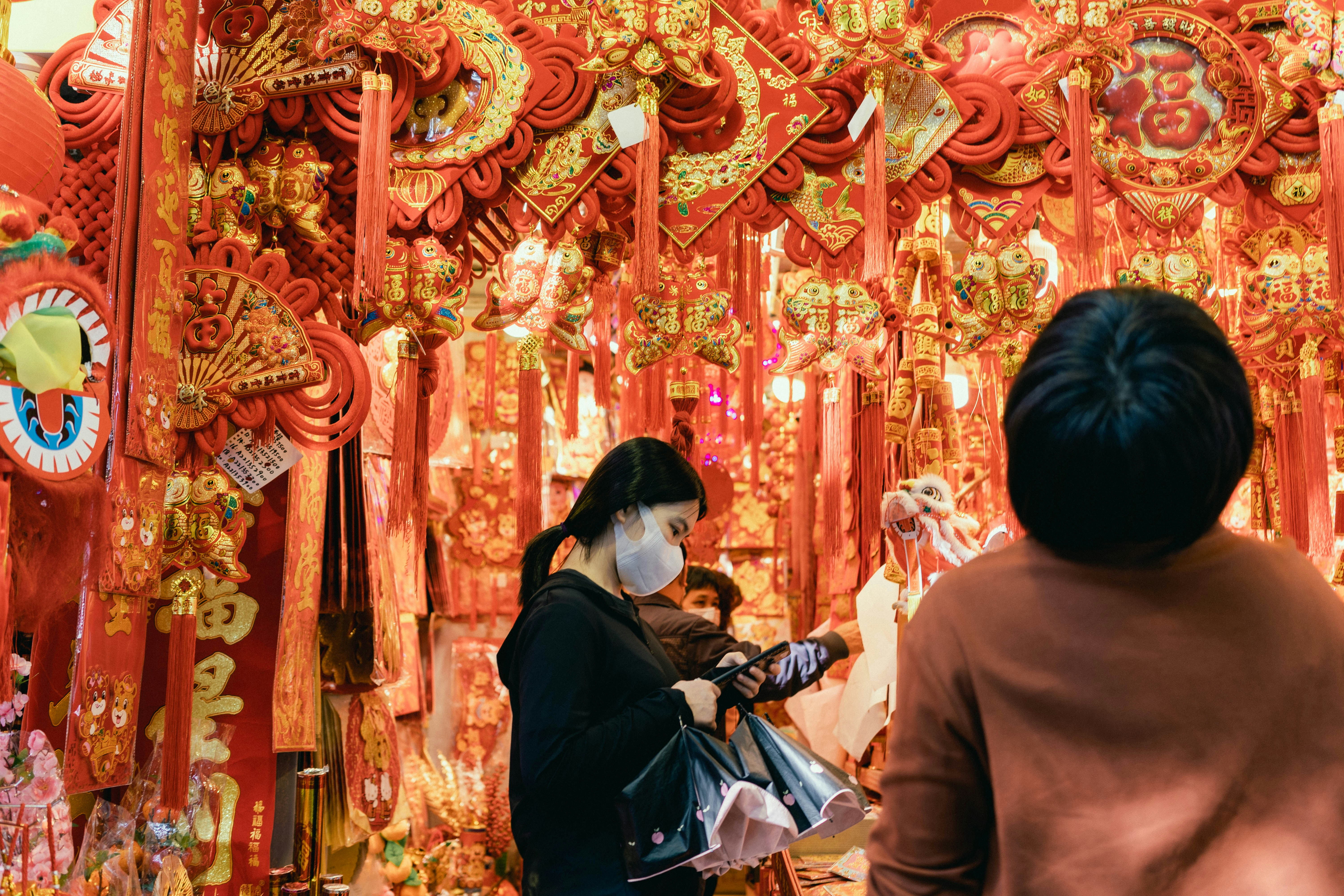 Masked Shopper Beneath a Sea of Red Lanterns at a Lunar New Year Market