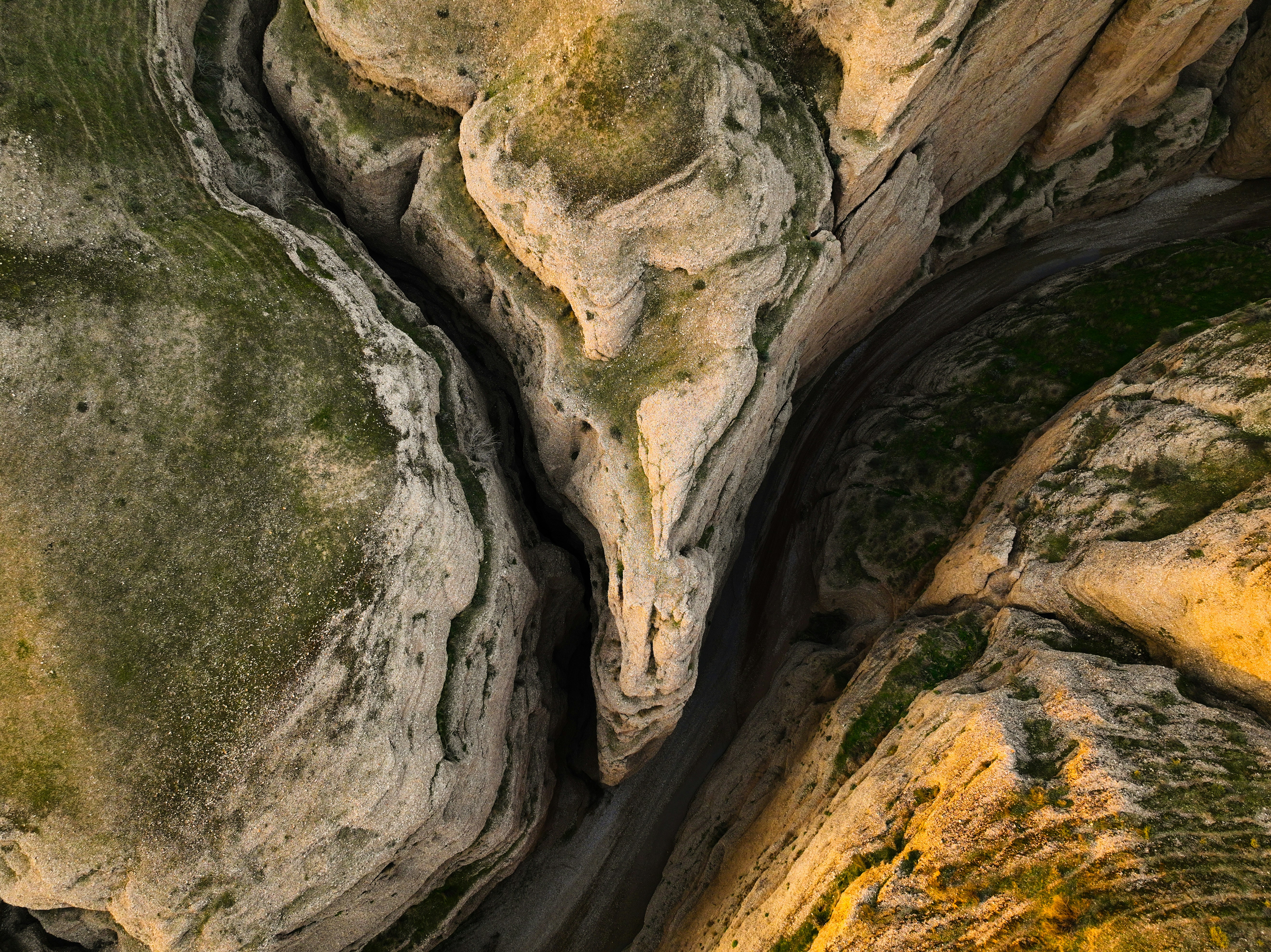 Aerial view showcasing intricate rock formations and a winding canyon, highlighting the natural textures and colors of the landscape.