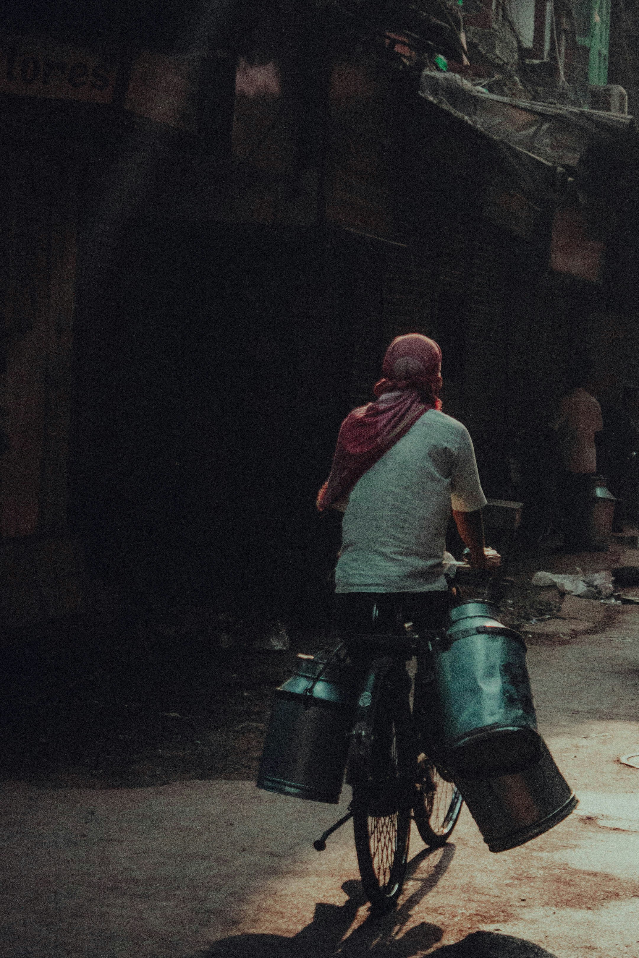 A man riding a bike with two buckets on the back of it photo – Free ...