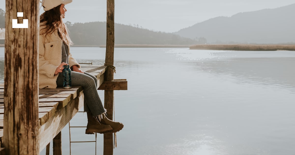 Foto Una Mujer Sentada En Un Muelle Junto A Un Cuerpo De Agua Imagen