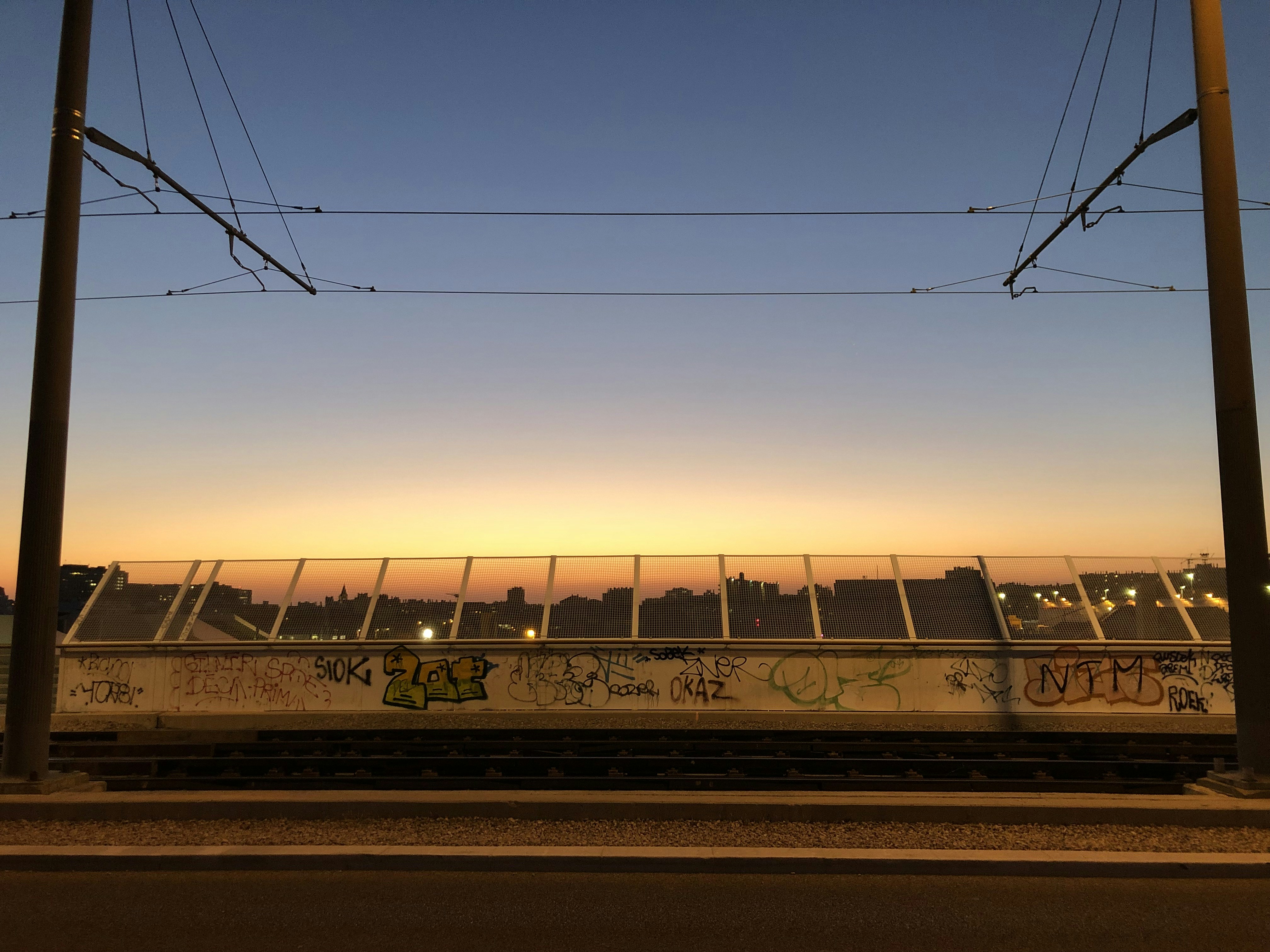 Foto El sol se está poniendo detrás de una valla con graffiti en ella ...