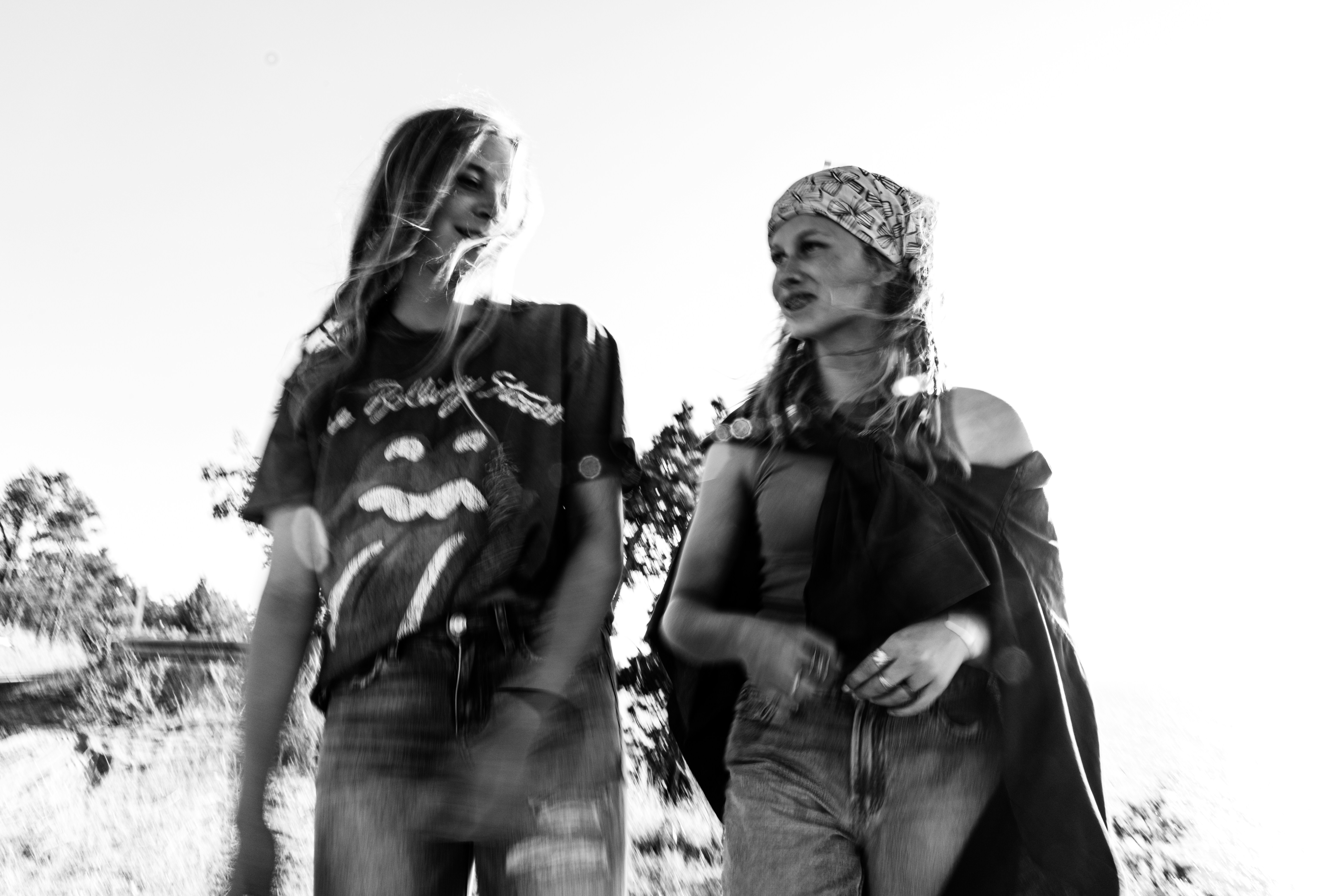 Two friends sharing a moment outdoors, dressed in casual attire and exuding a carefree spirit. The image captures the essence of friendship in a natural setting.