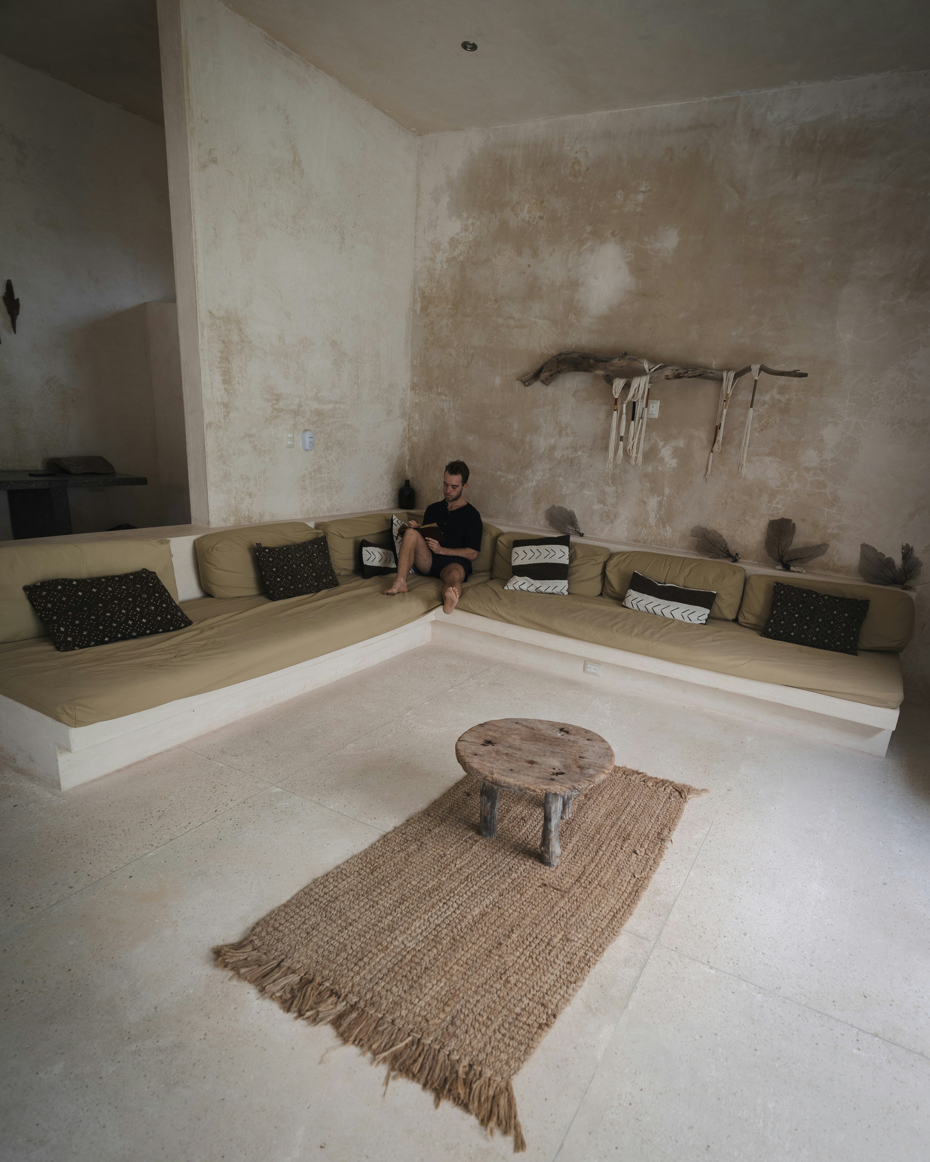 Cozy living space featuring a curved sofa, rustic wooden coffee table, and a textured rug, with a person engaged in a quiet moment.
