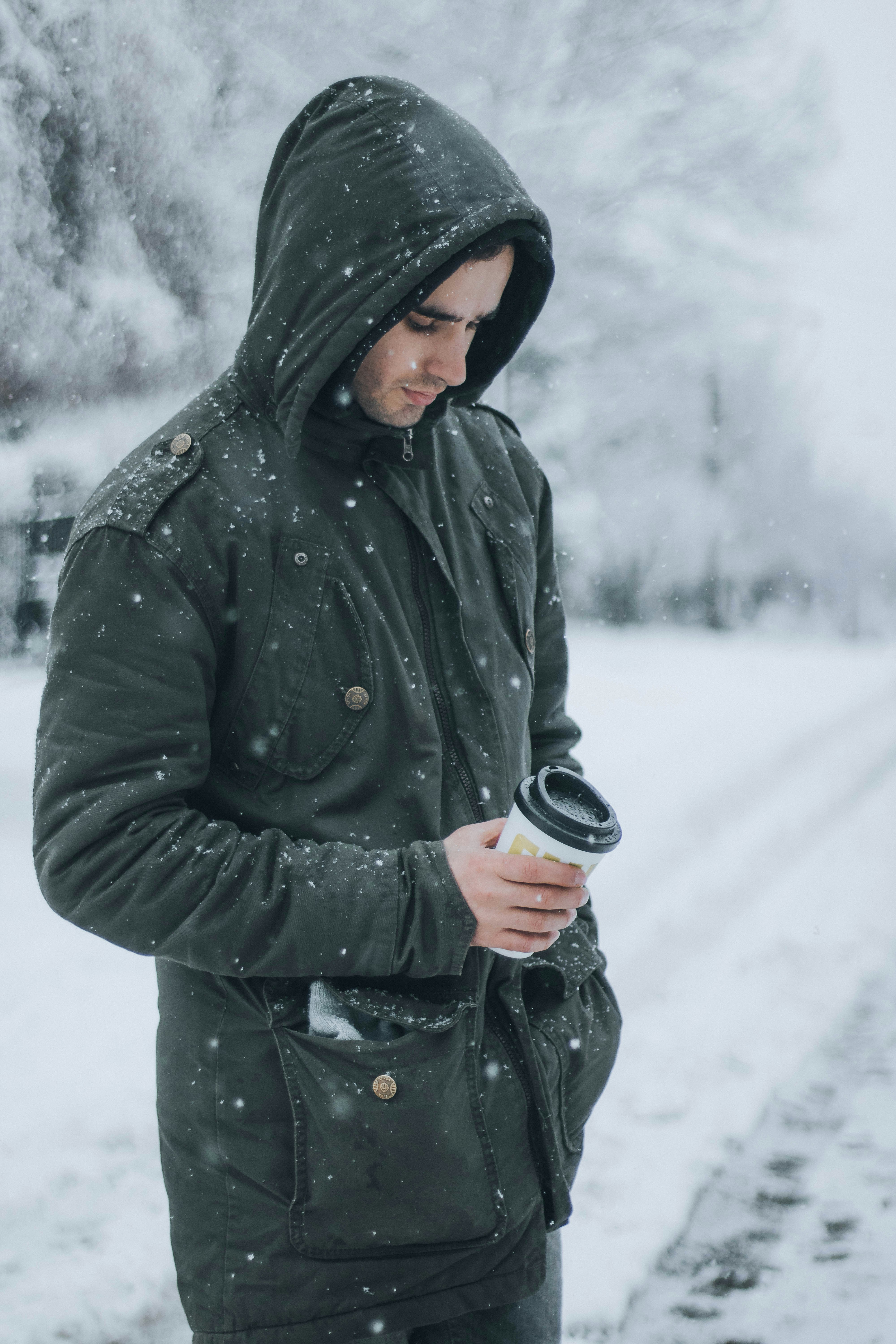 a man standing in the snow holding a cup of coffee