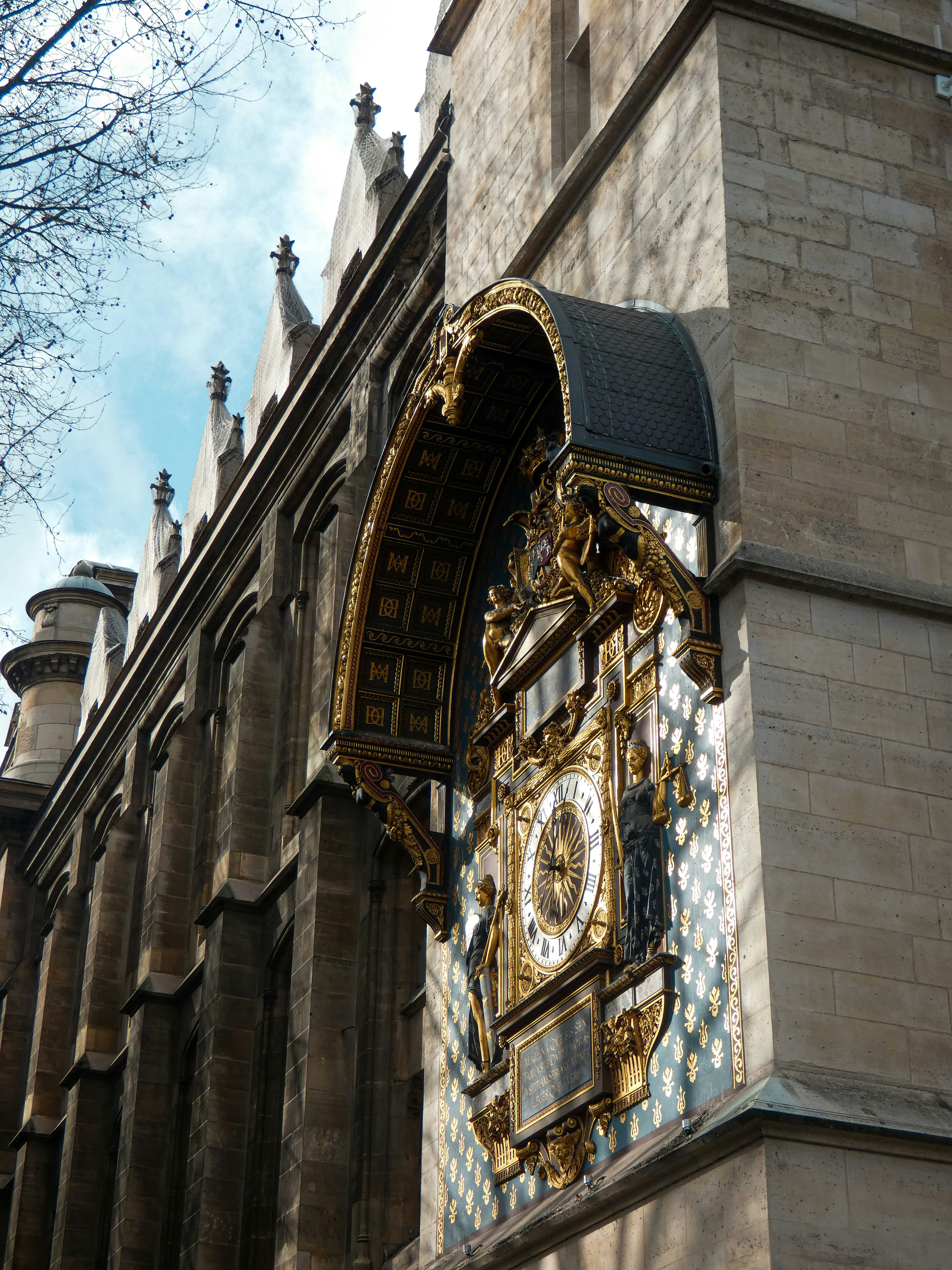 Gilded Clock Under a Gothic Canopy on a Stone Facade