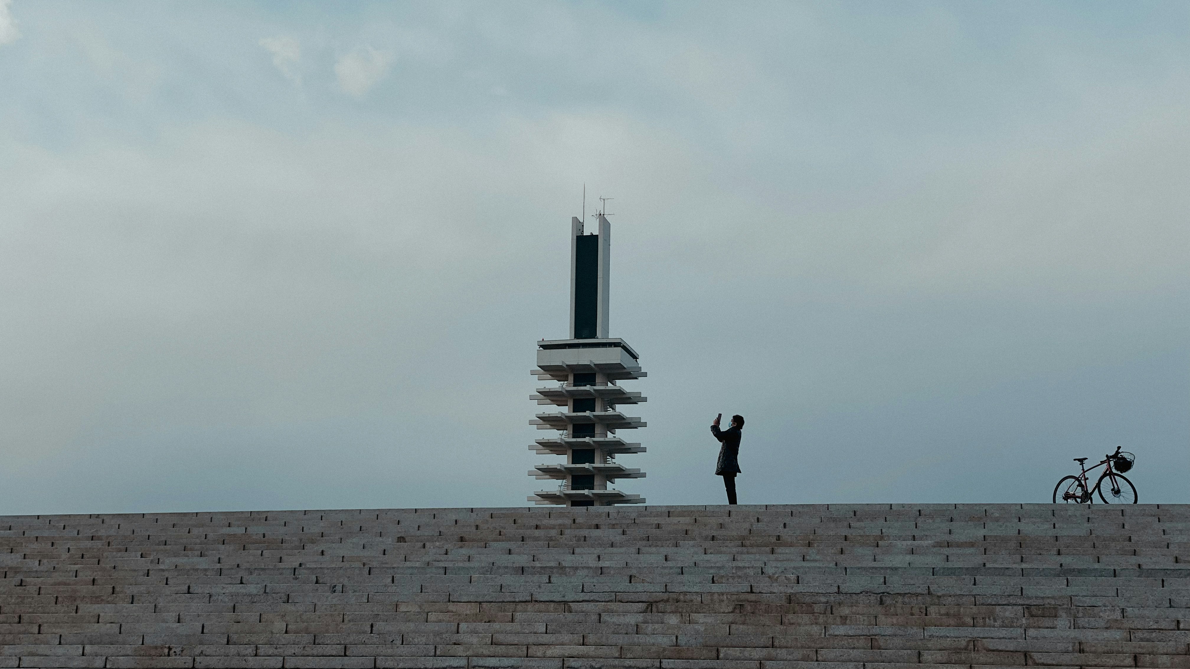 Rooftop Gesture Under a Minimalist Skyline: Figure & Stacked Tower