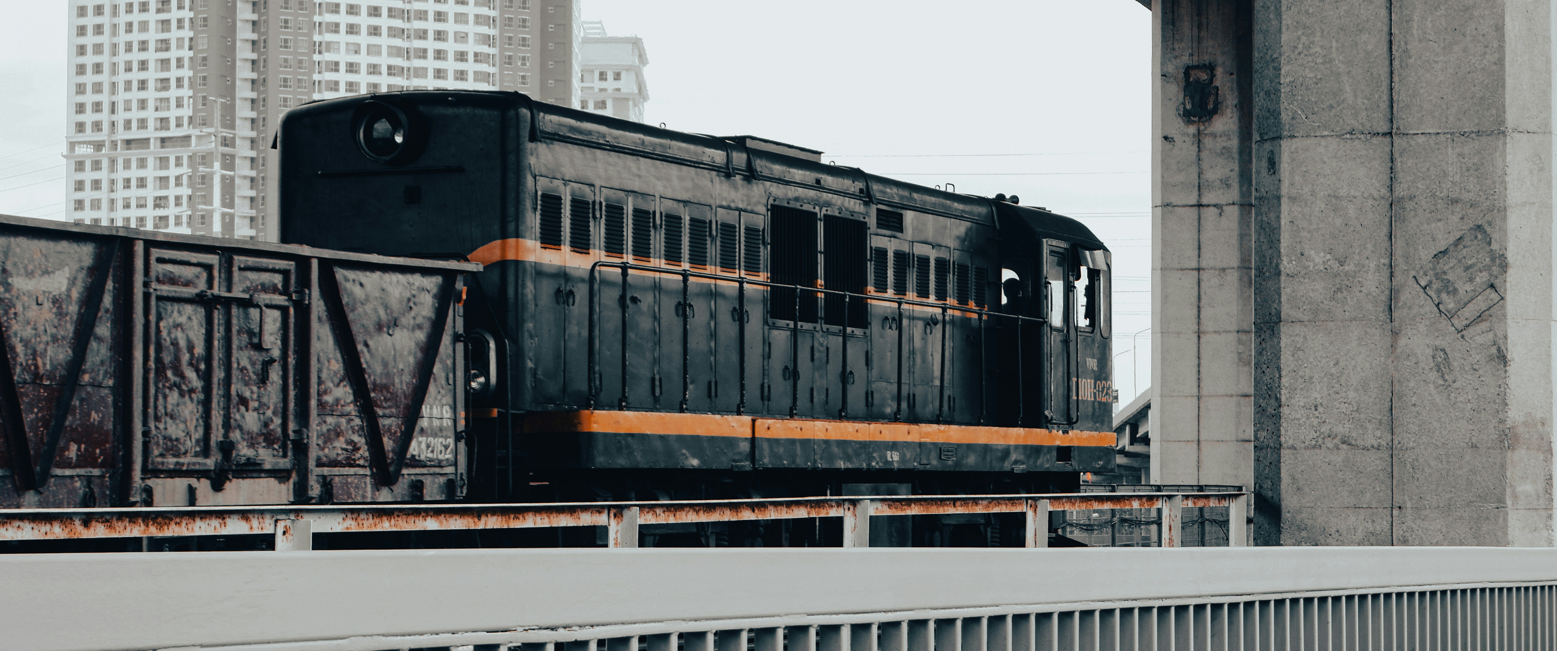 A vintage locomotive traversing an urban landscape, juxtaposed against modern skyscrapers. The scene captures the essence of industrial nostalgia.
