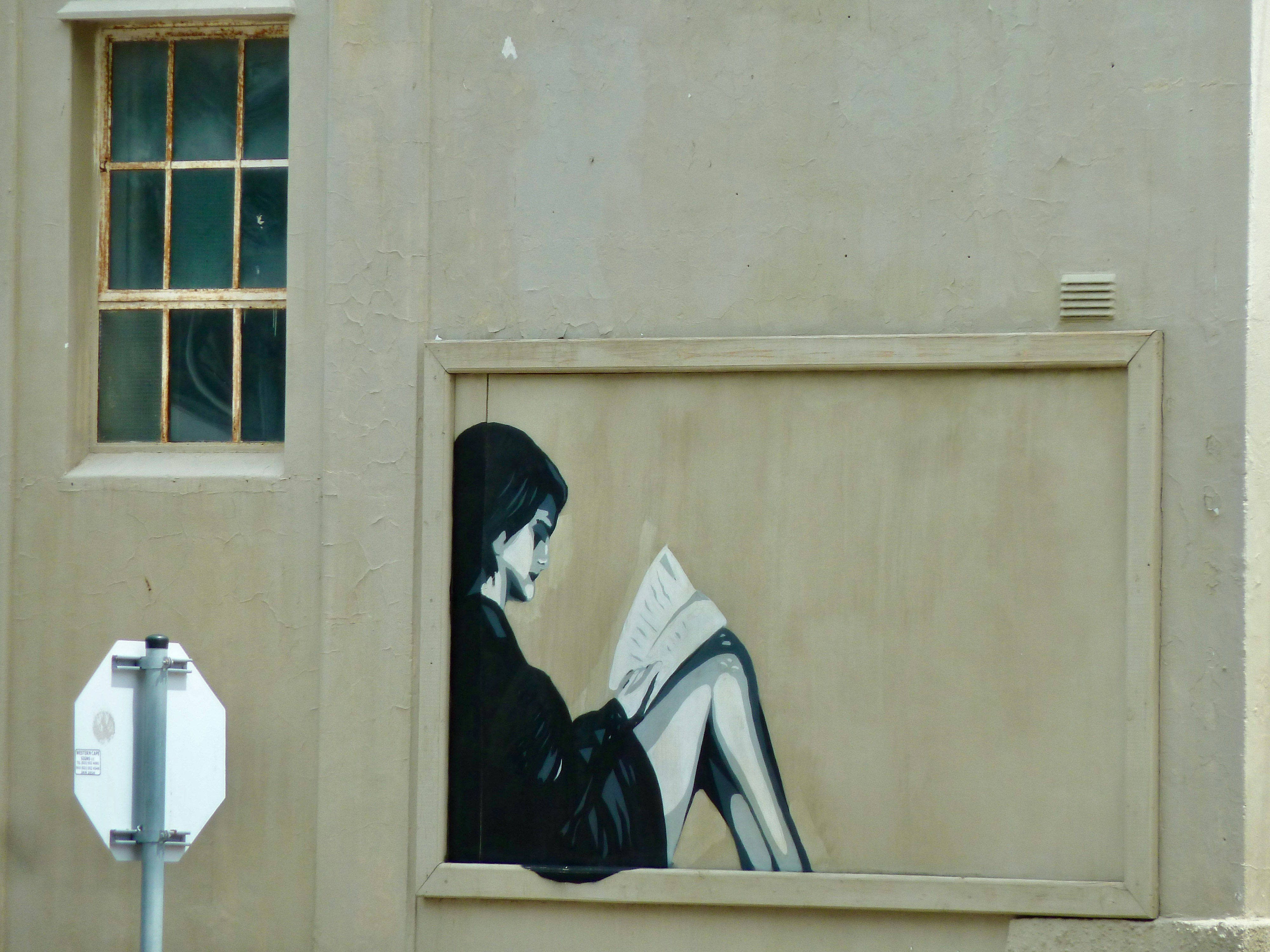 The Reader in the Frame: A Solitary Figure on a City Wall