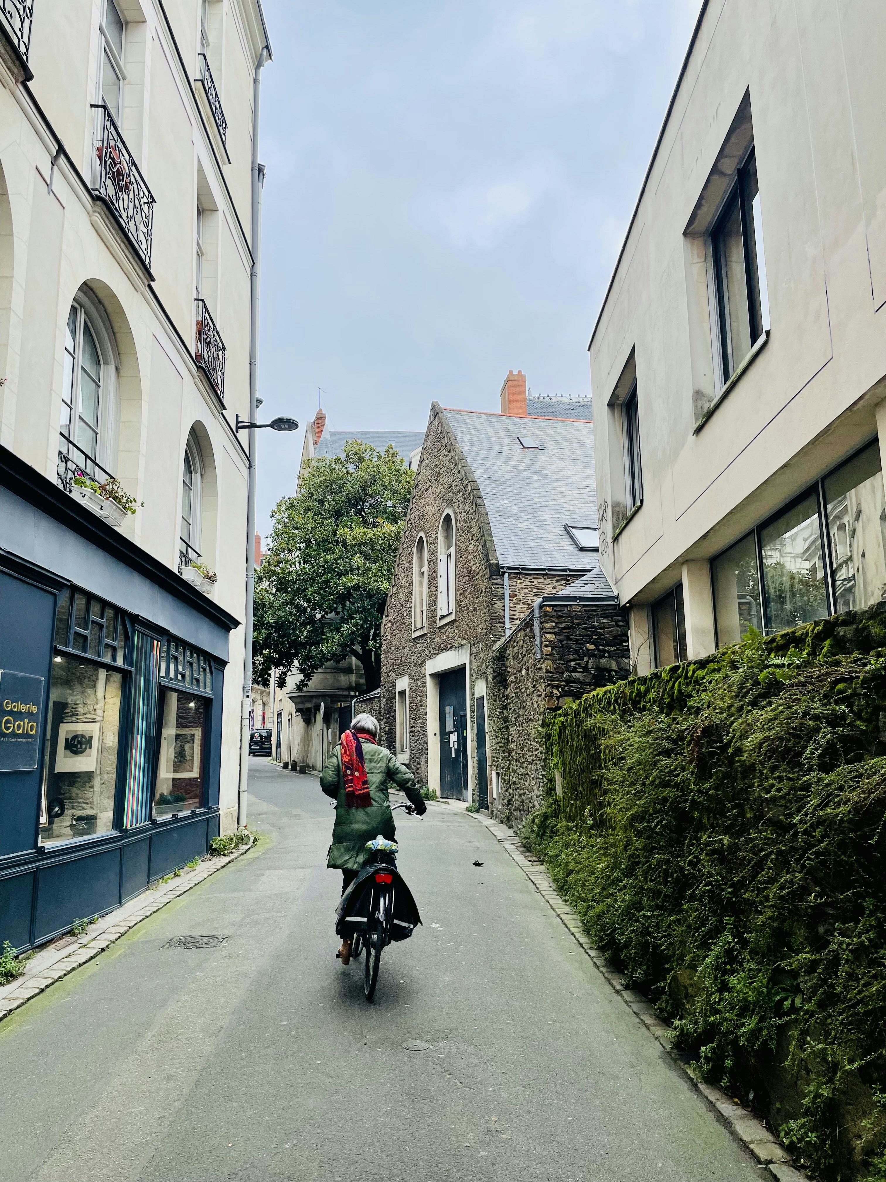 Cyclist in a Narrow Village Lane Between Stone and Plaster