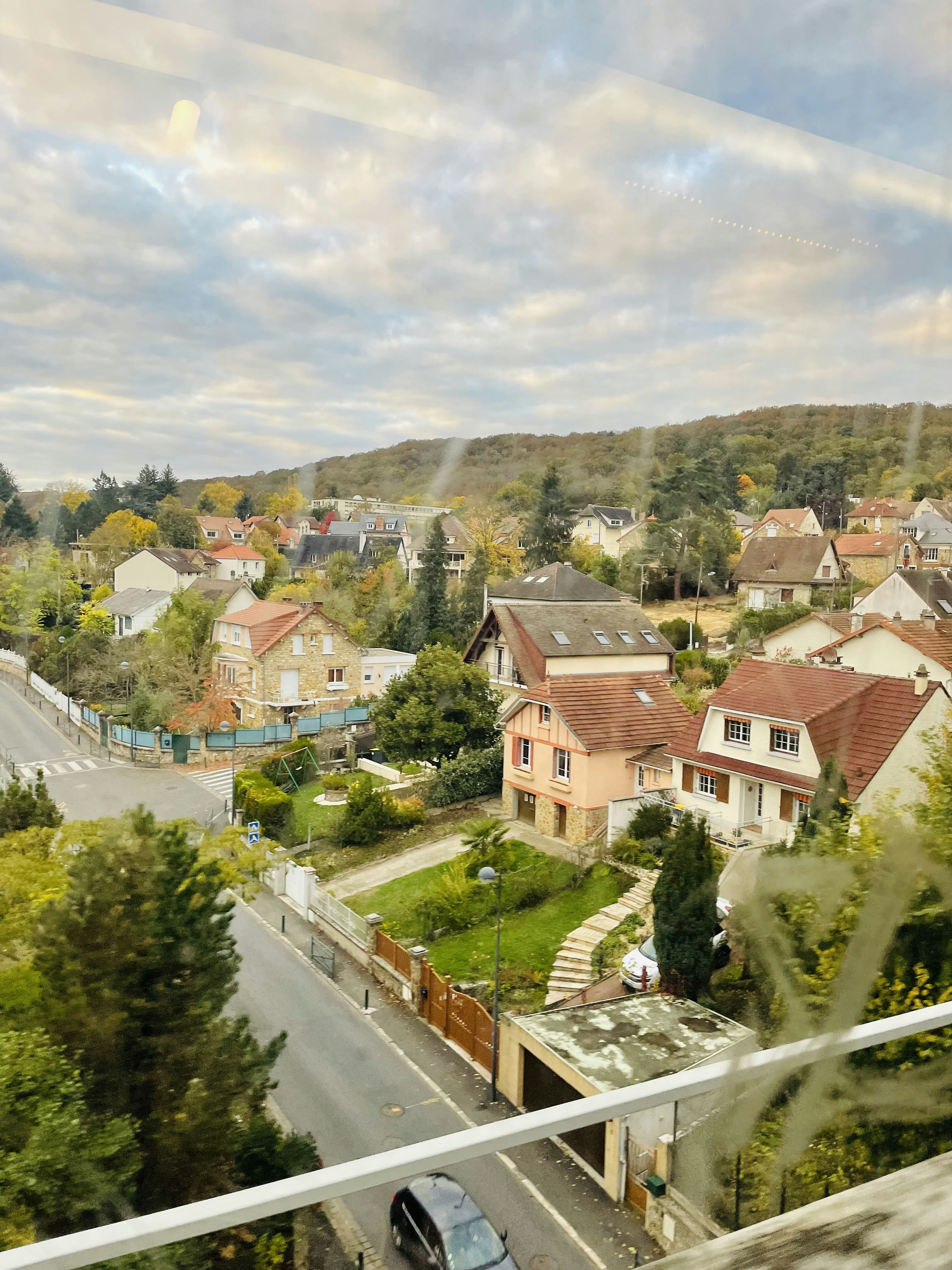 Charming suburban landscape featuring a mix of houses and greenery under a cloudy sky. The scene captures the essence of quiet residential life.
