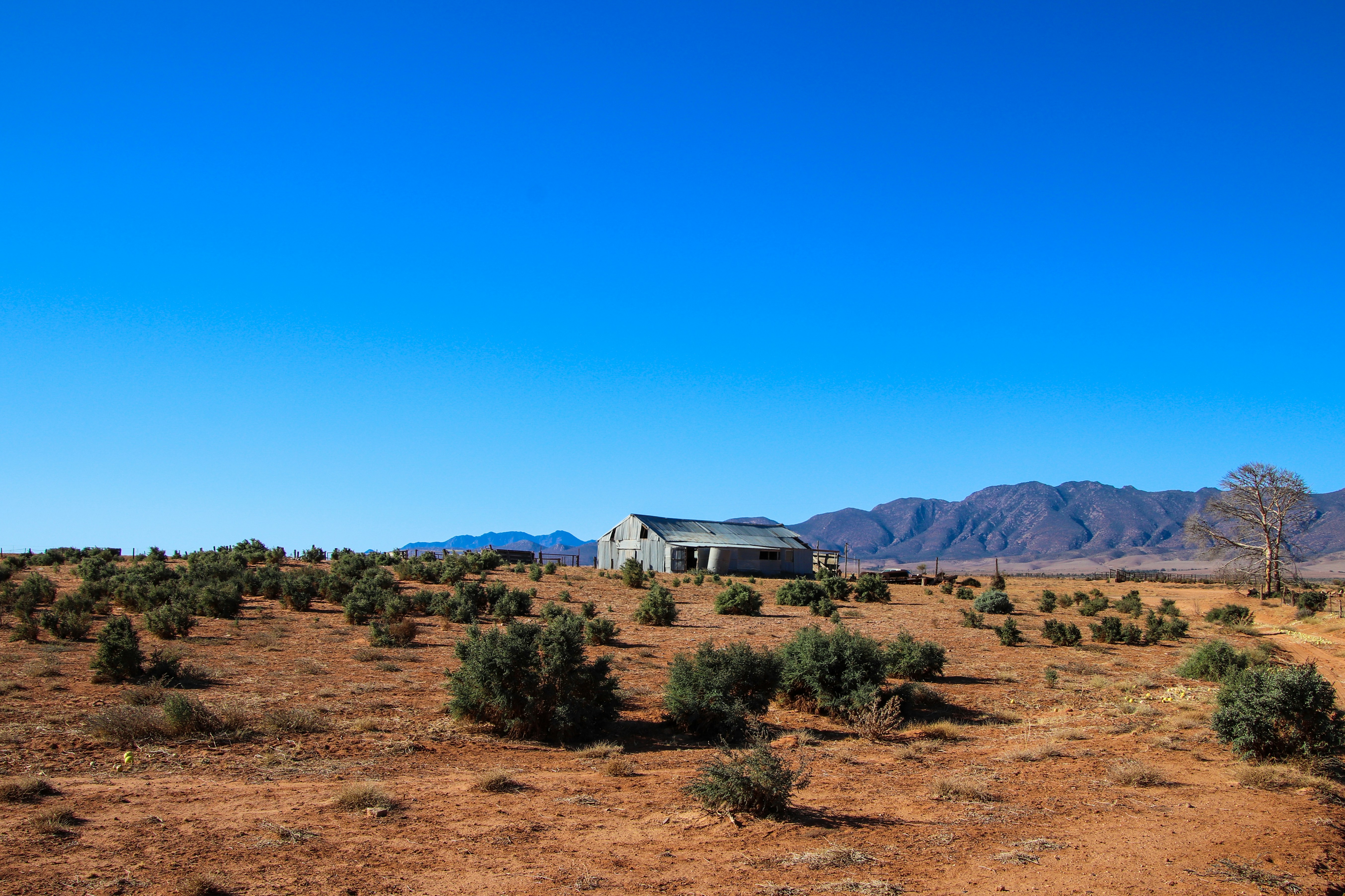 a house in the middle of a desert with mountains in the background
