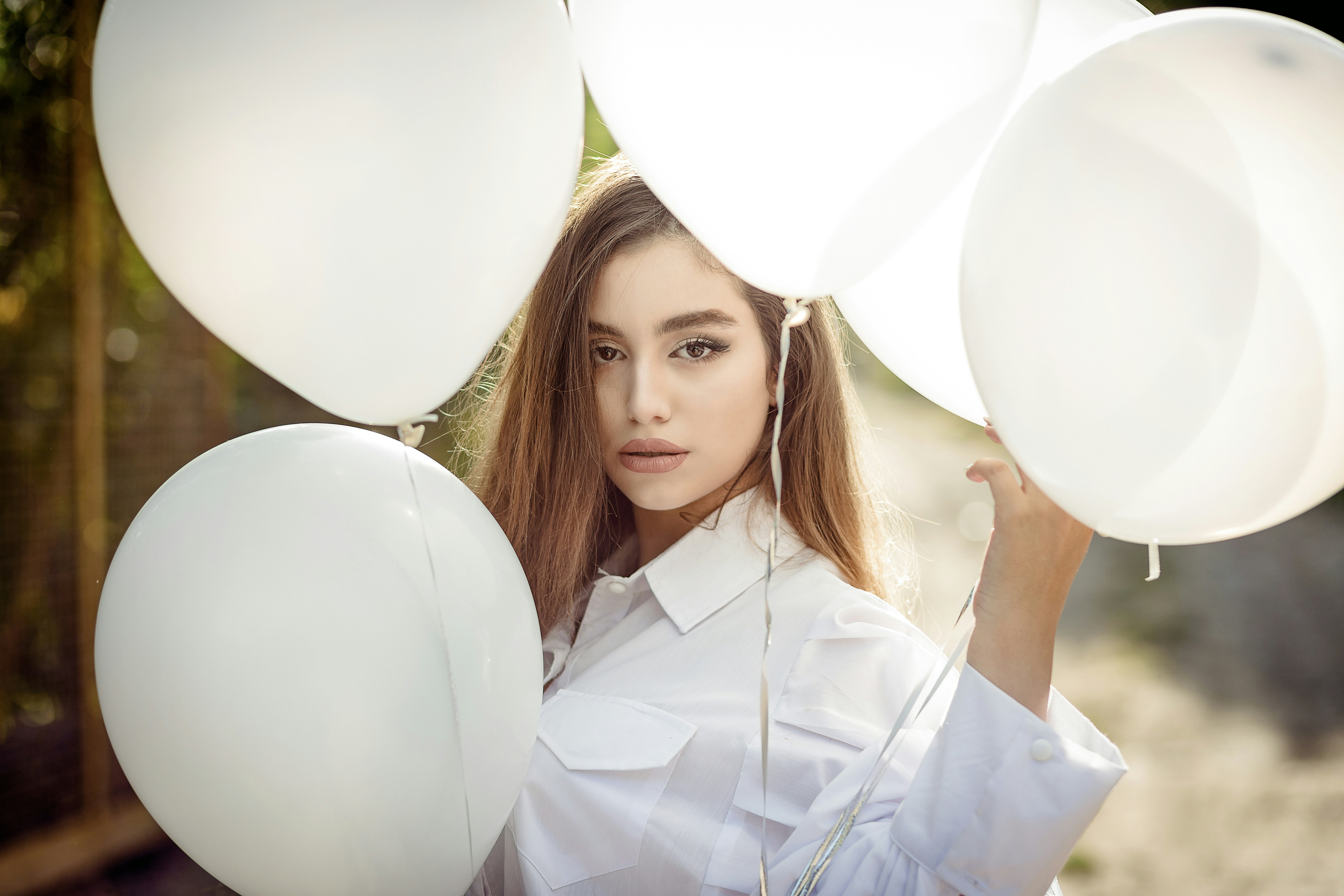 A woman holding white balloons in front of her face photo – Free ...